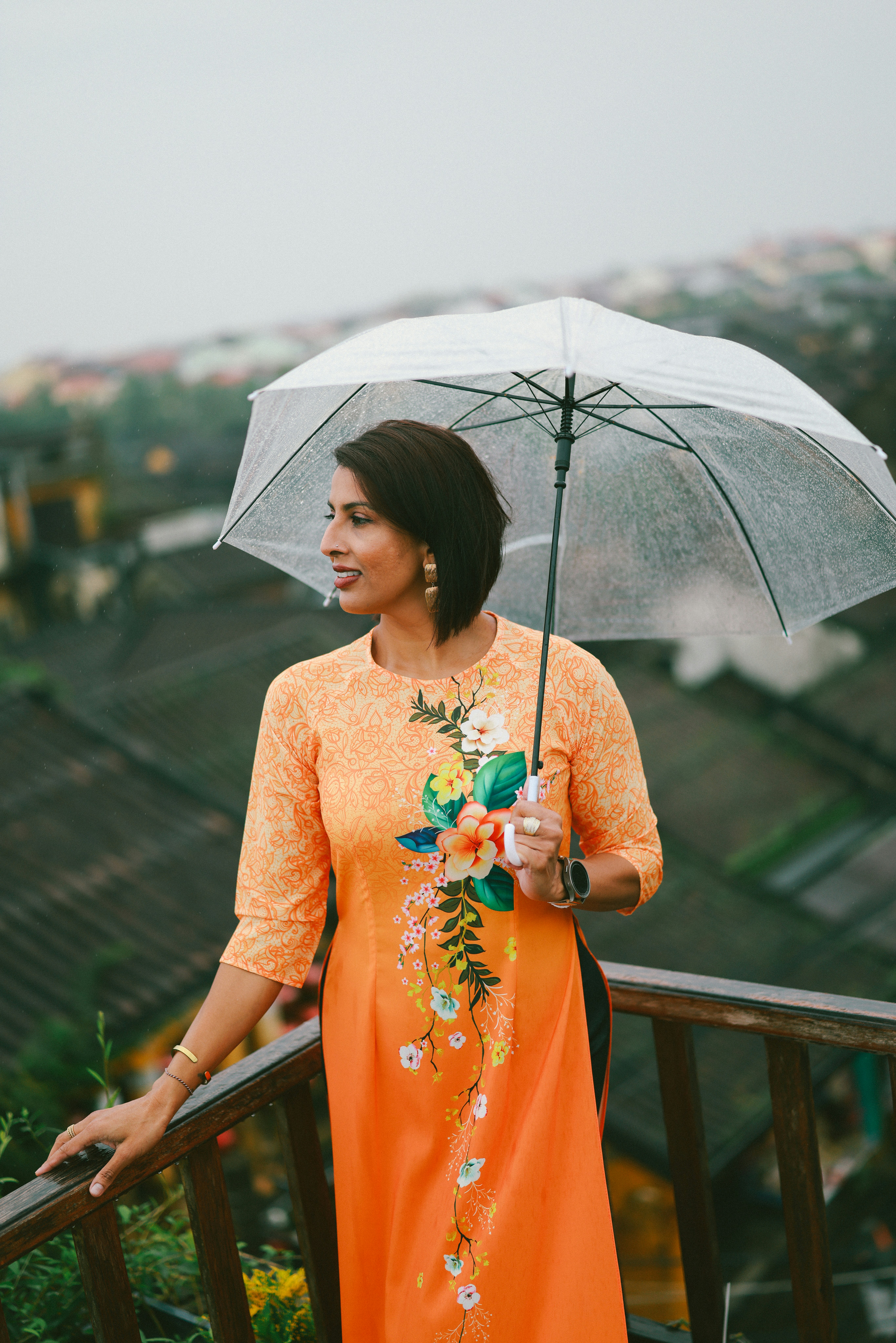 Apricot dress under a silver umbrella on a rainy balcony