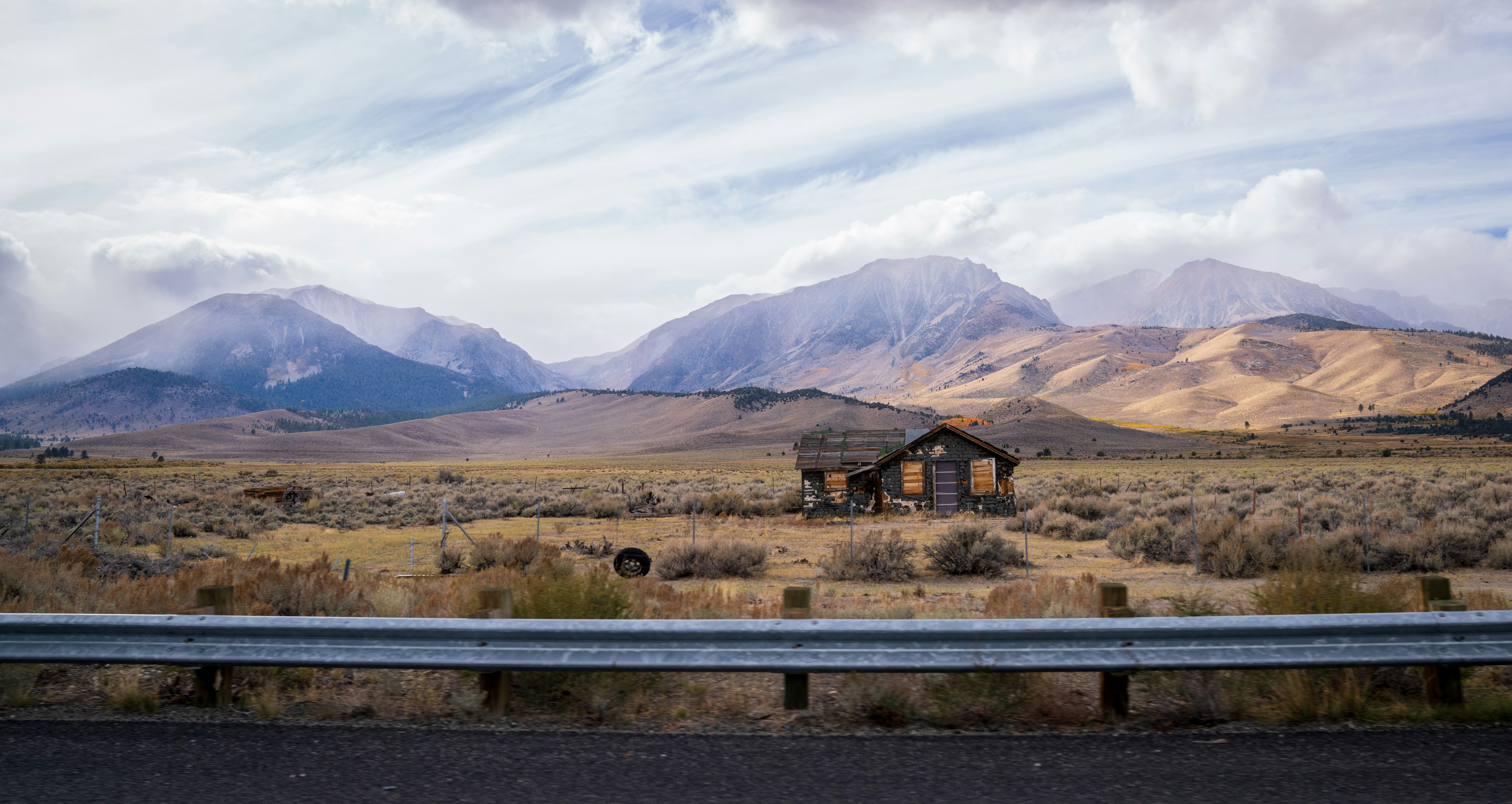 Lone Cabin in a High-Desert Valley Beneath Mountain Skies