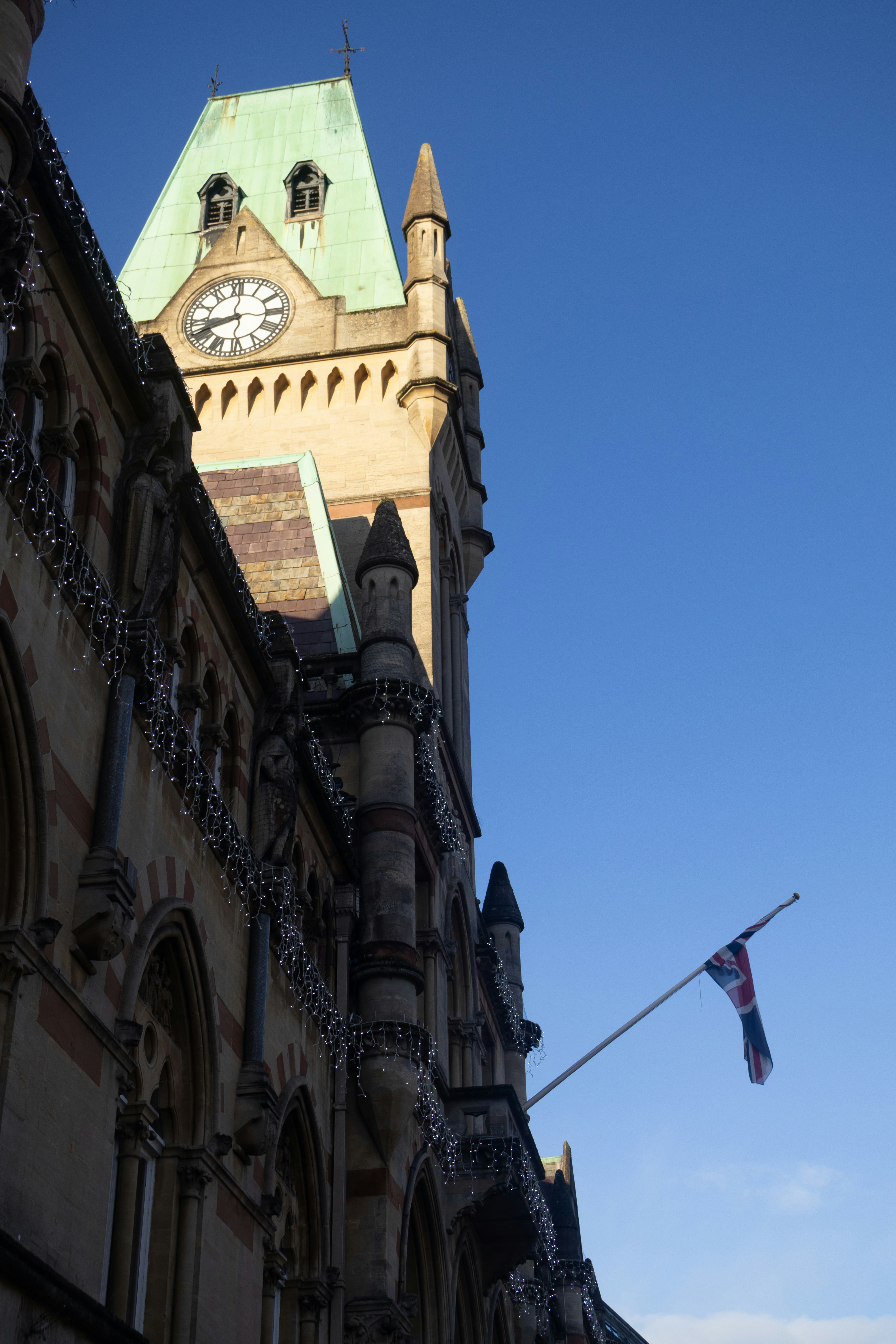 Clock Tower on a Clear Day: Copper Roof, Stone Facade, and Waving Flag