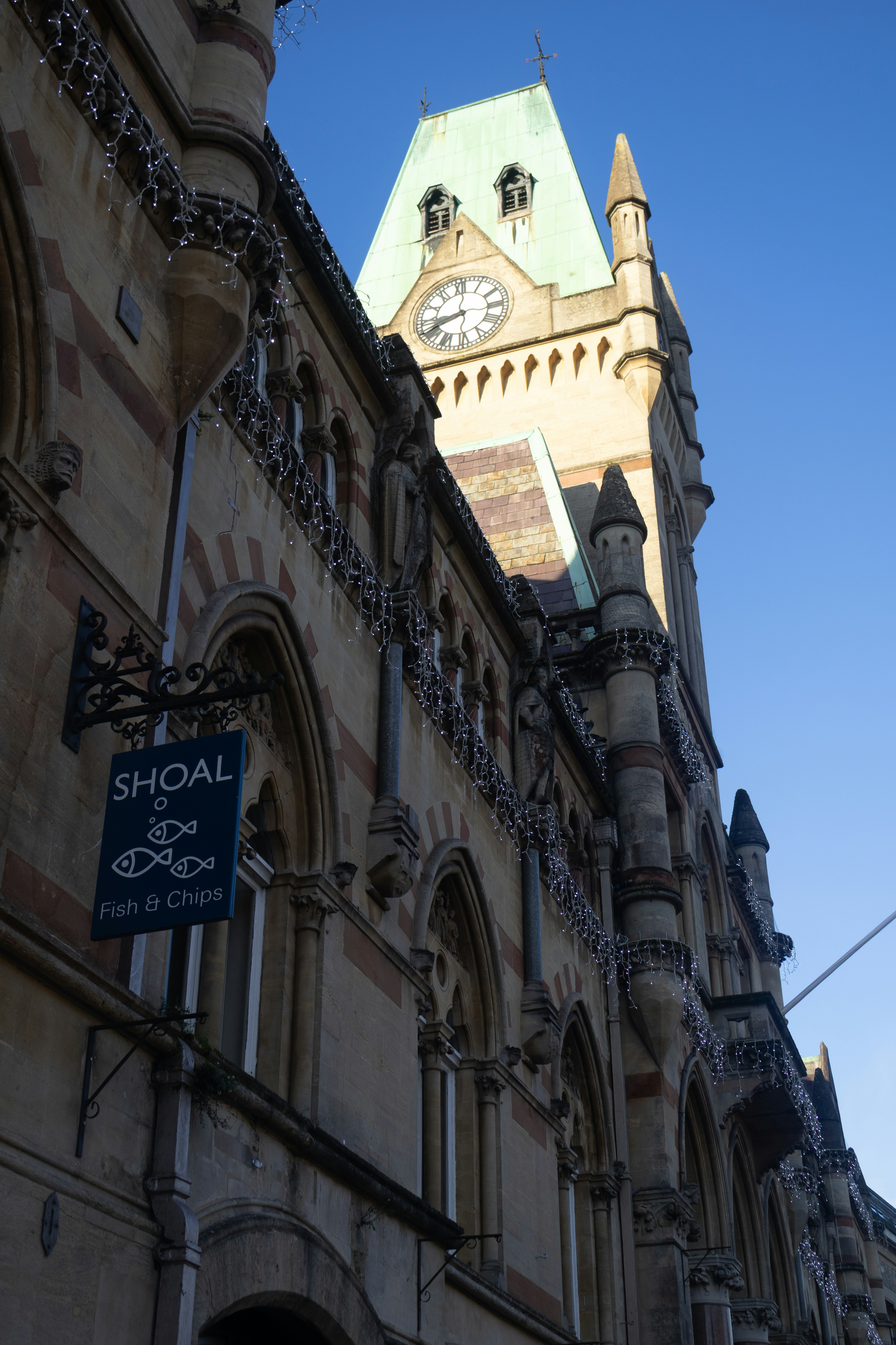 Clock Tower Above a String-Lit Stone Arcade
