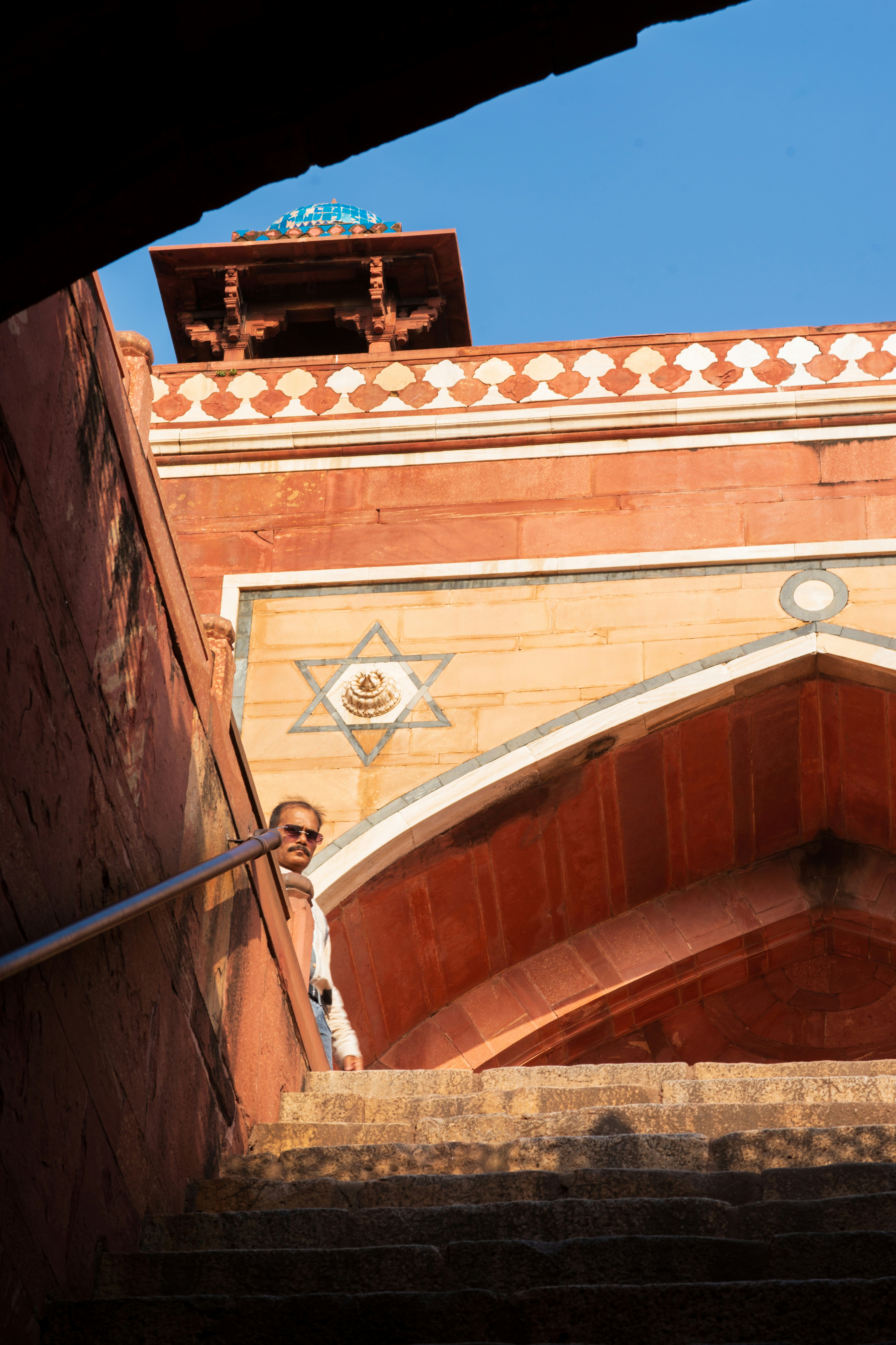 Sunlit Threshold: A Stranger Watches from the Red Stone Stairway