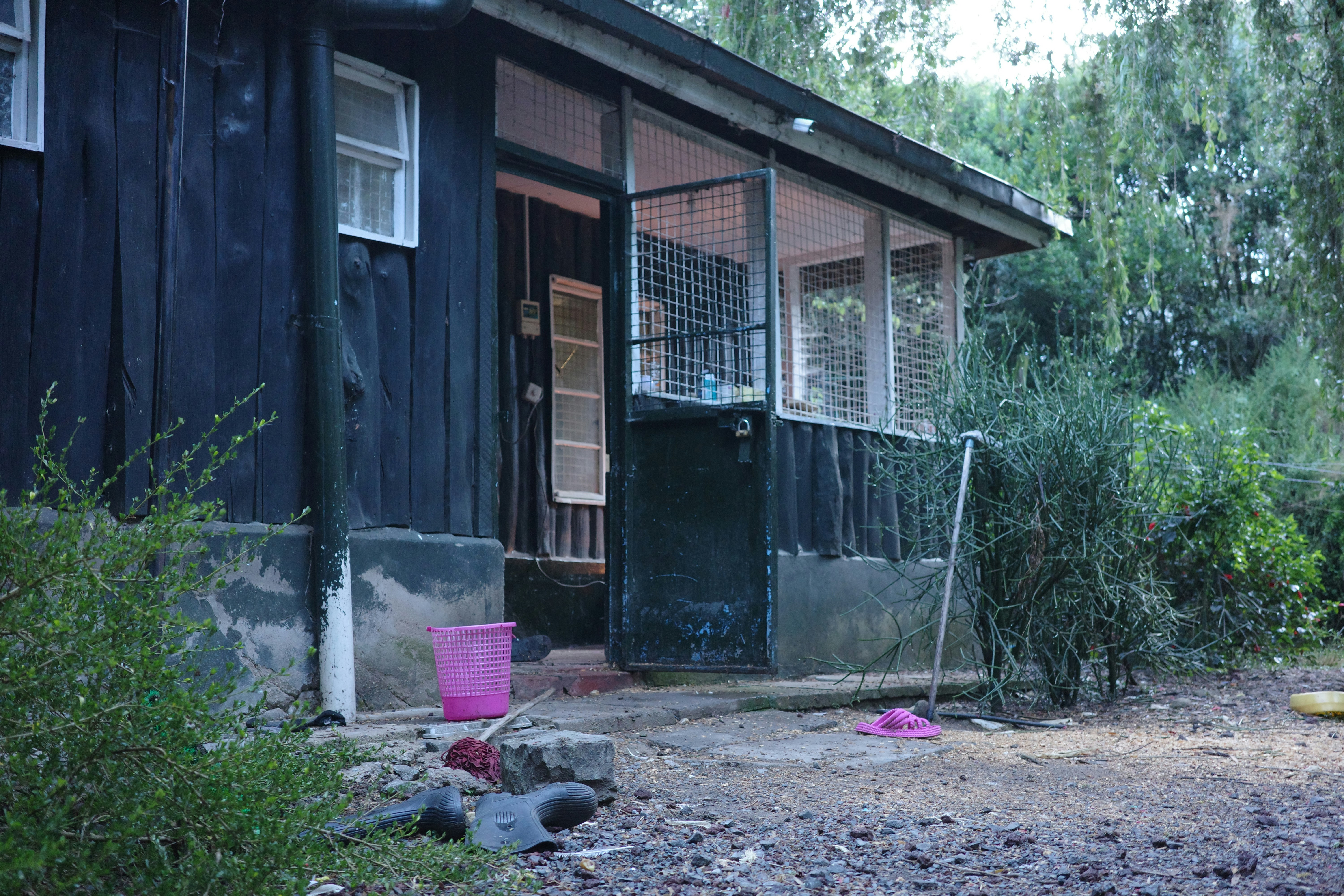 A farmer's residential house with some tools besides it and a boot laying on the floor.