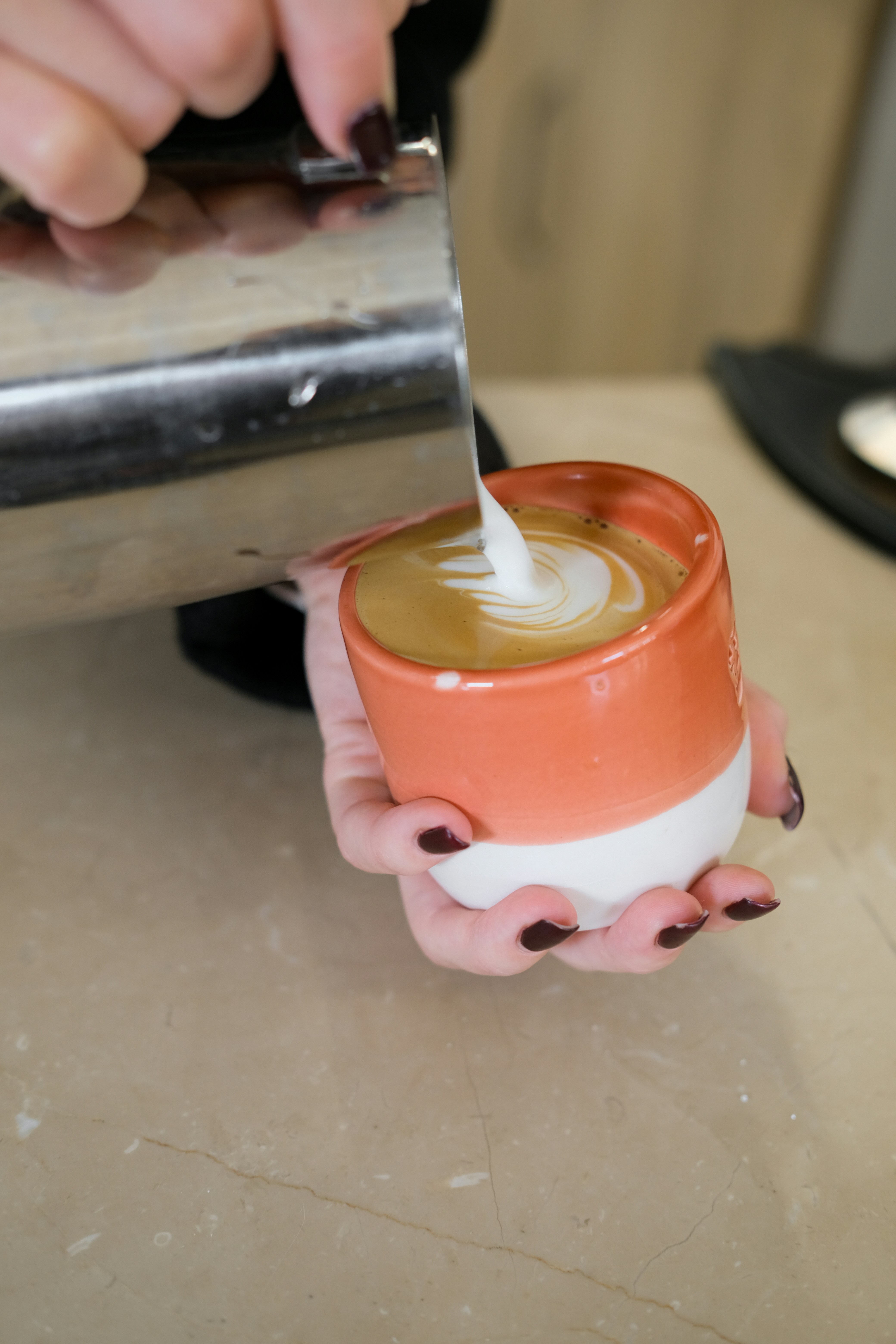 Milk Art in a Handheld Cup: A Close-Up Latte Pour