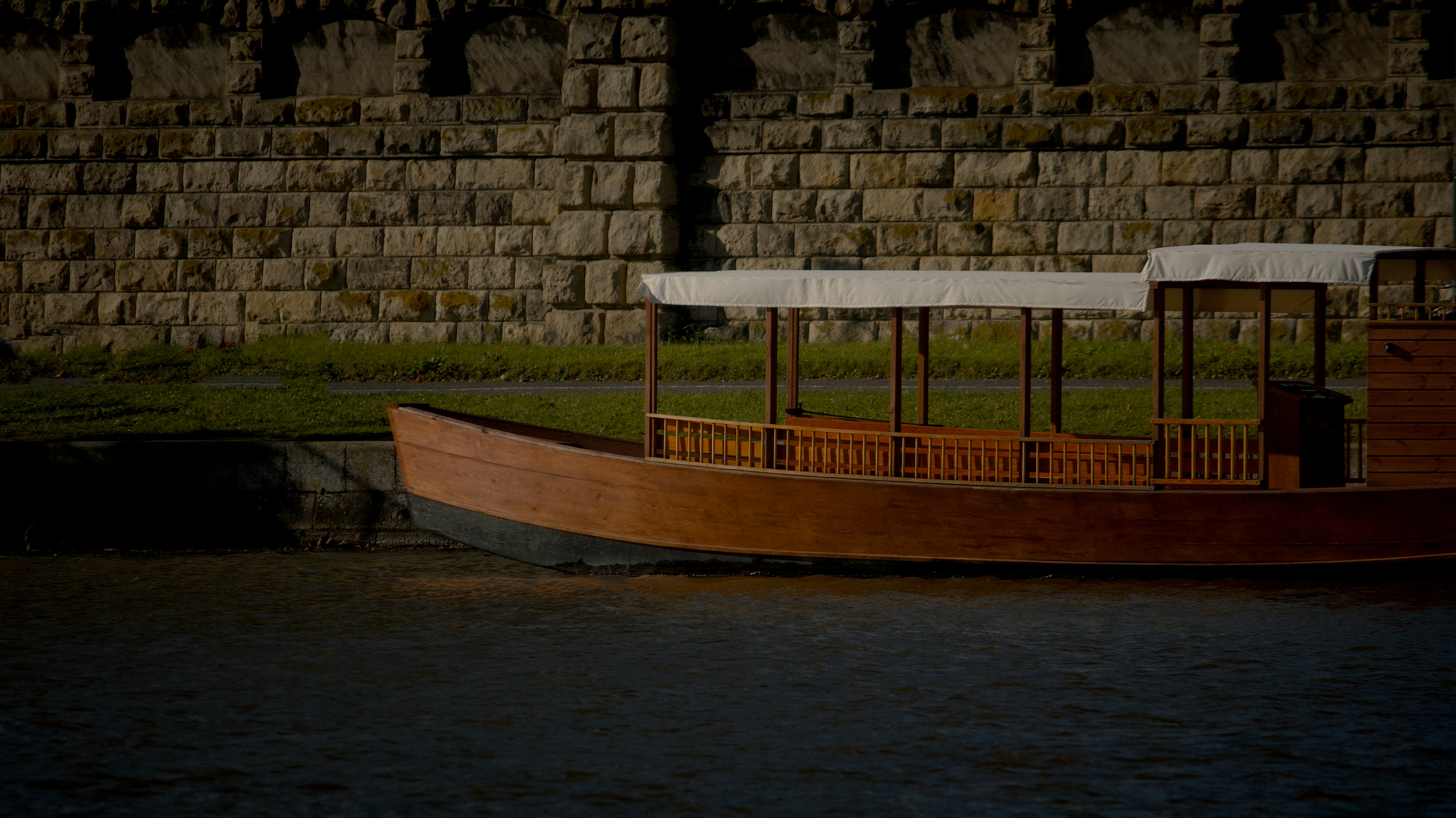 Wooden Boat by the Waterline under a Stone Embankment