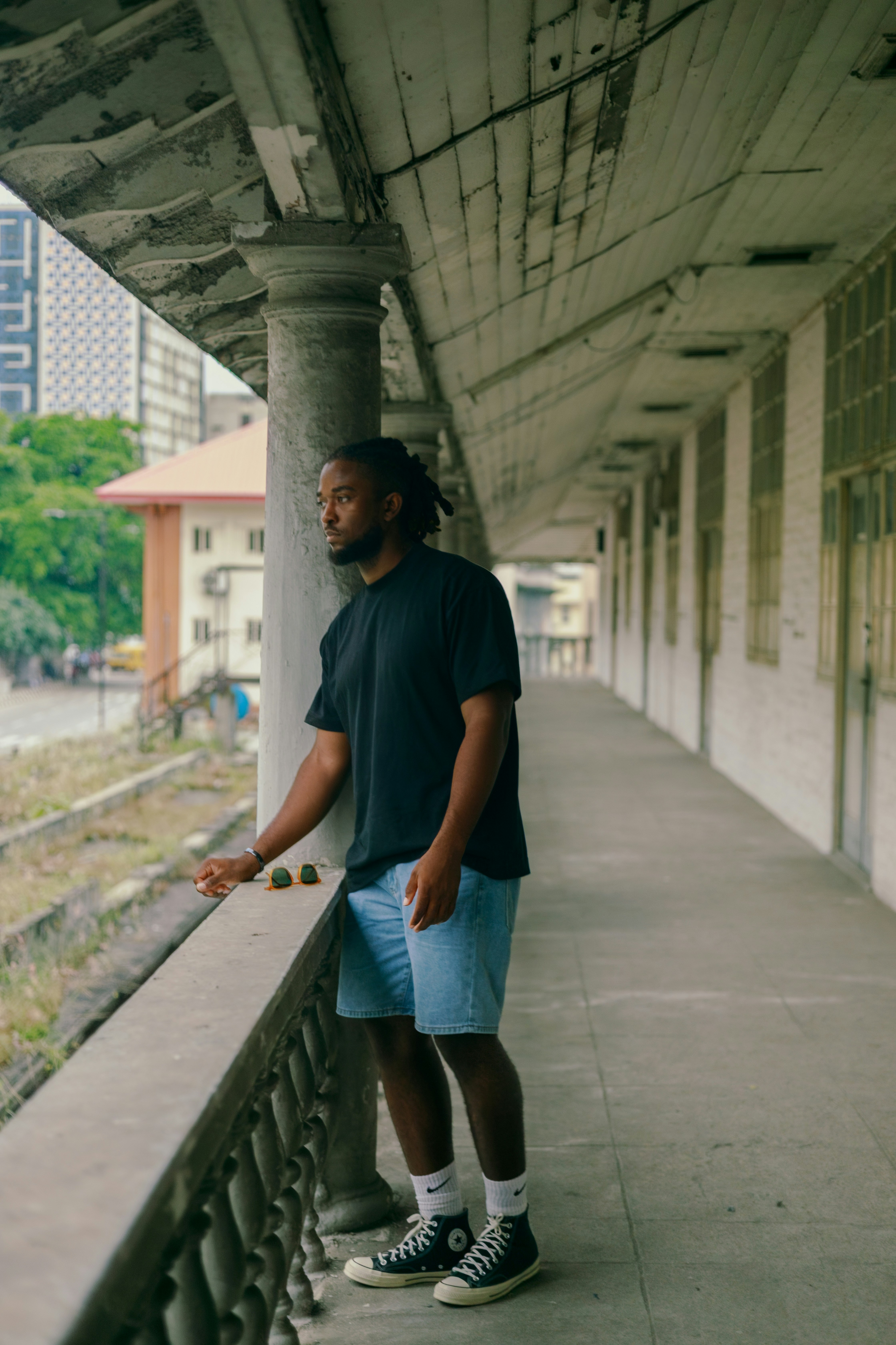 Colonnade Contemplation: Portrait on a Shaded City Balcony
