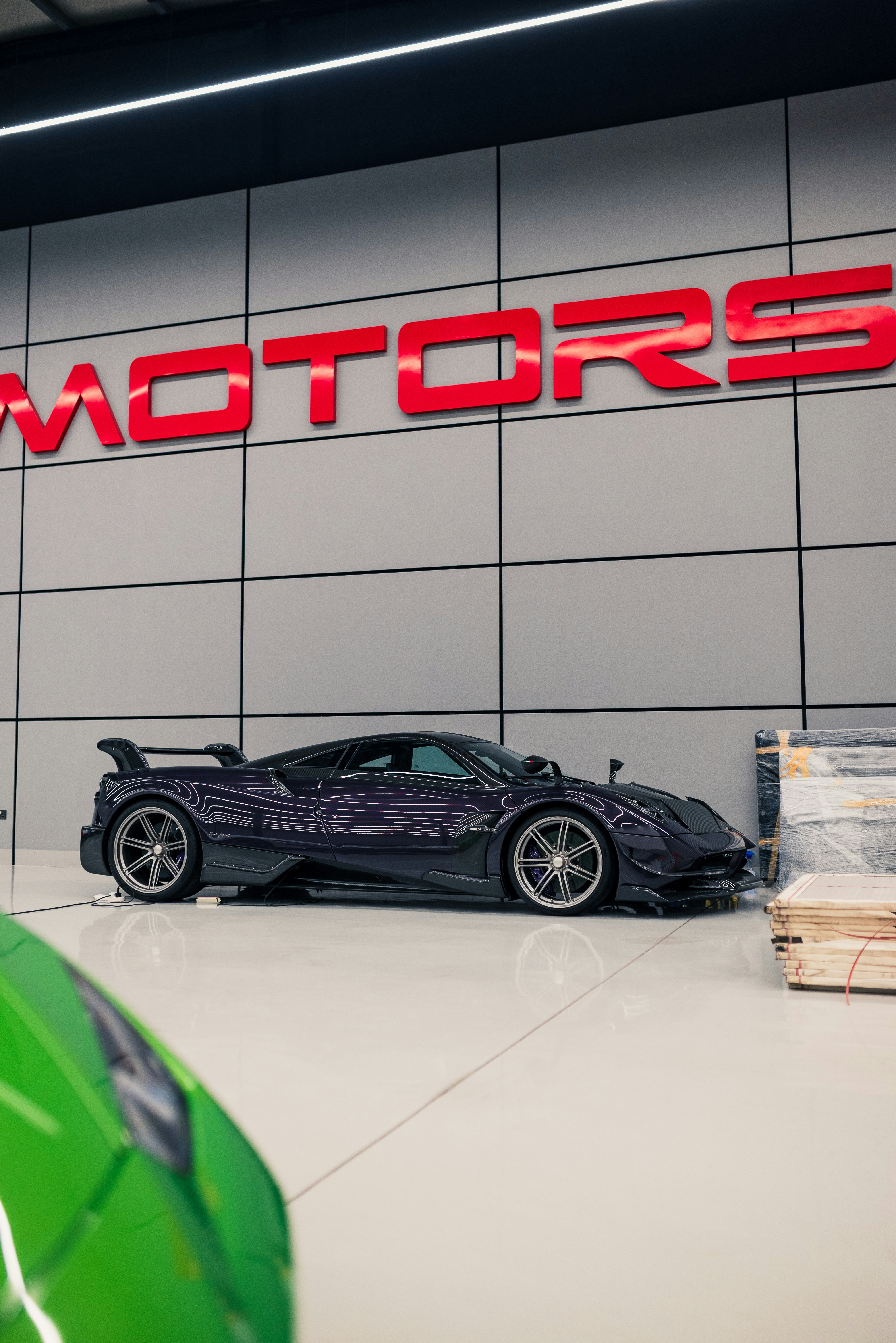 Purple Hypercar Beneath the Red MOTORS Sign