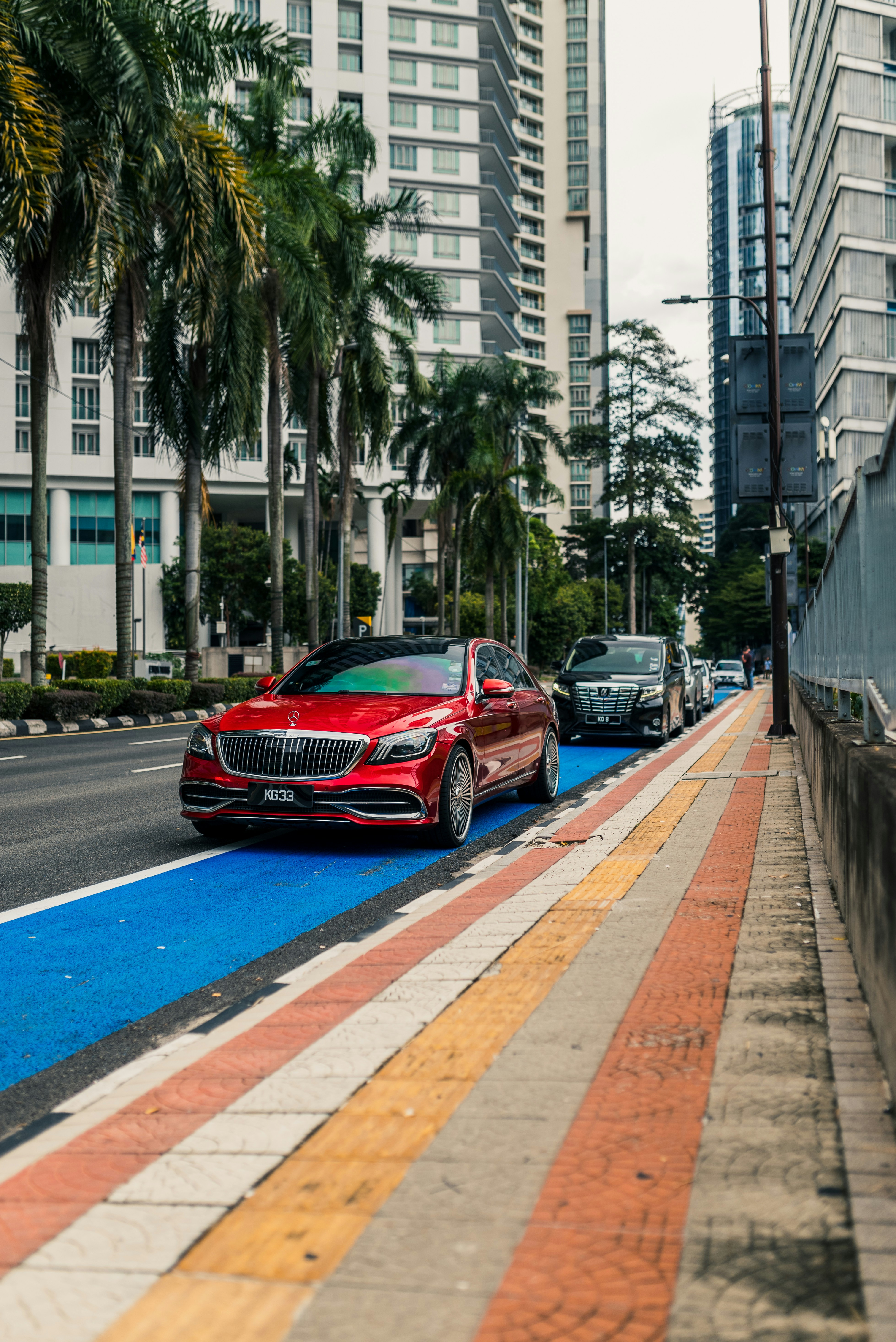Crimson Sedan on a Palm-Lined Urban Boulevard