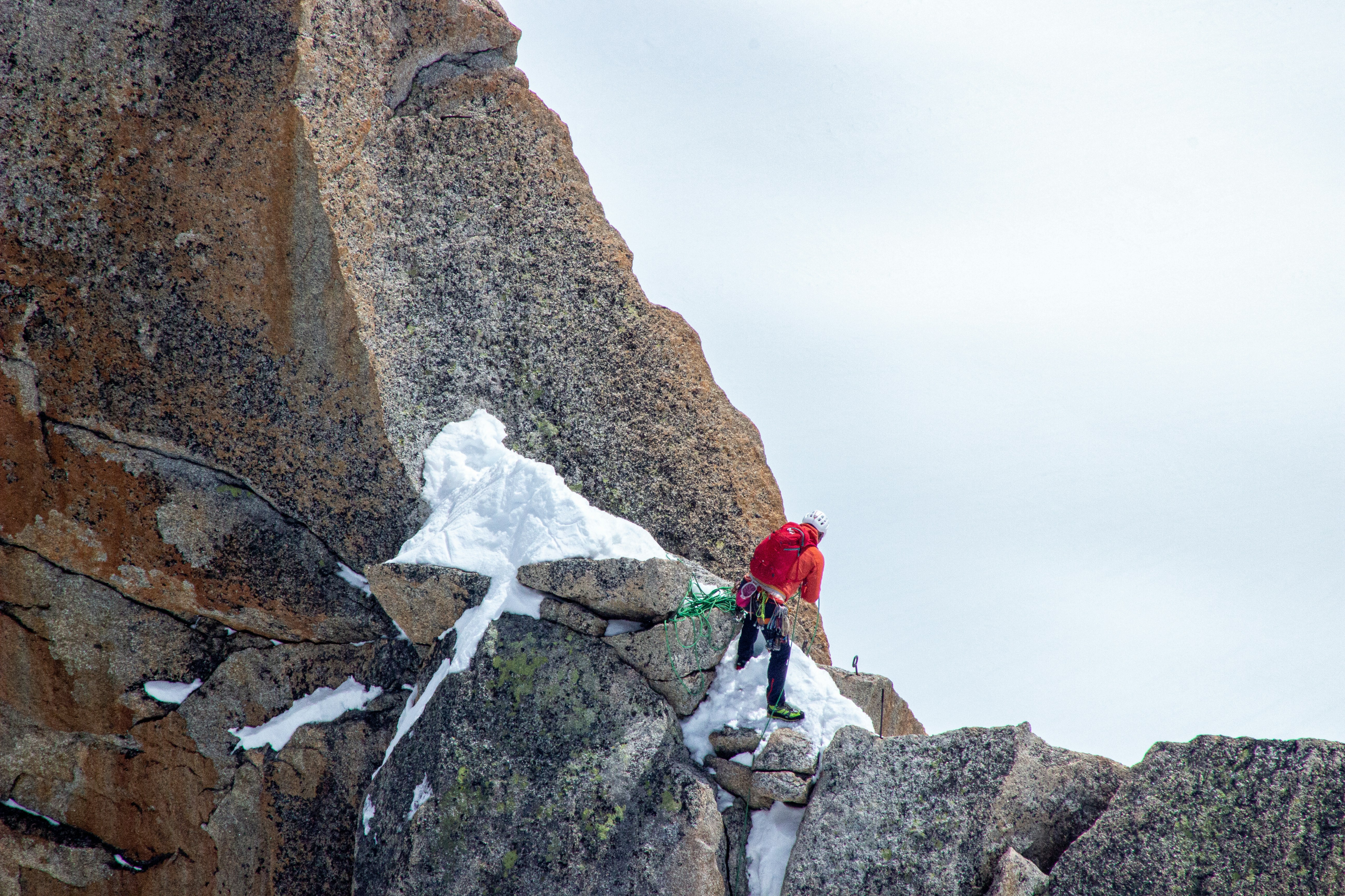 Crimson Climber on a Snow-Dusted Granite Ridge