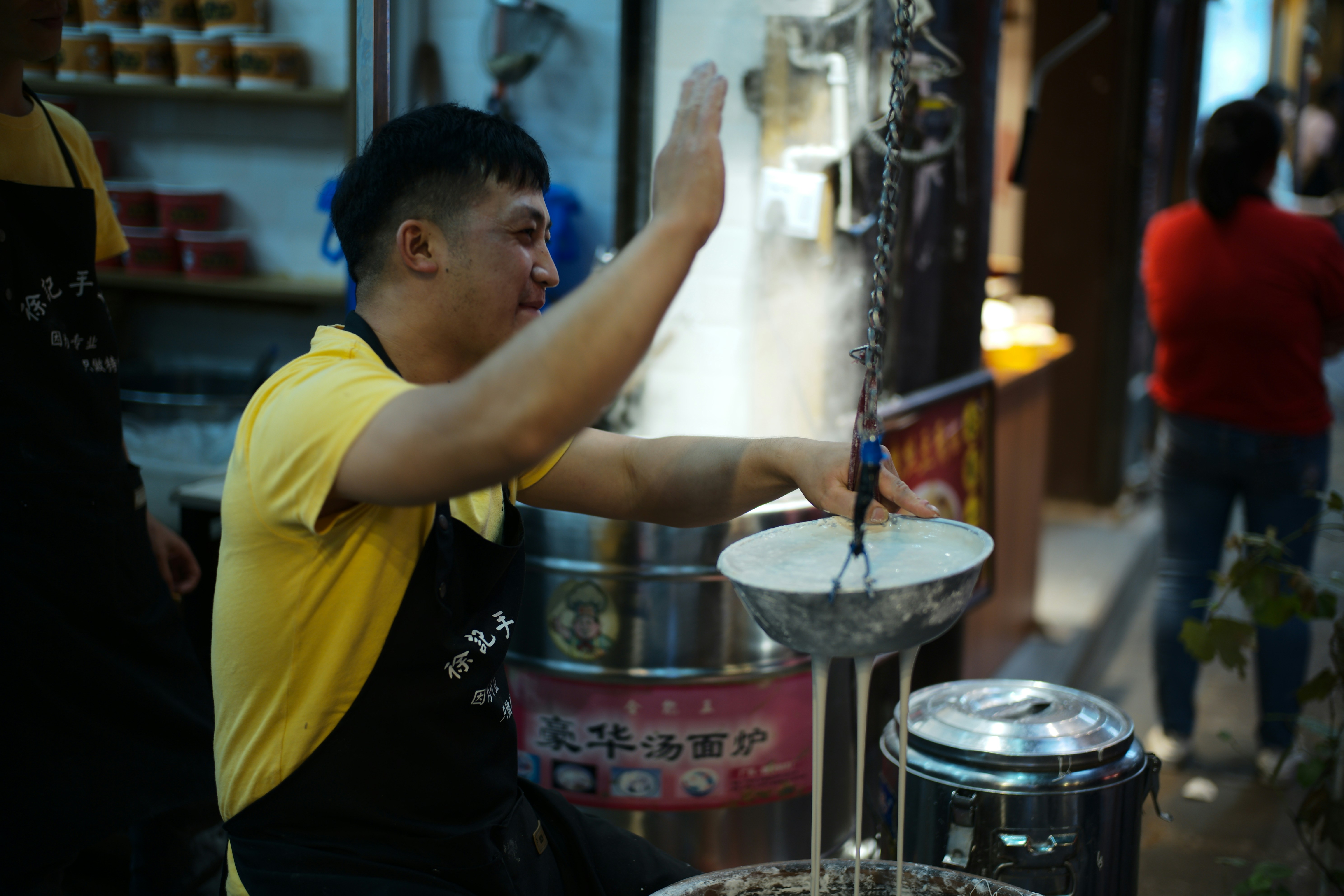 Steam and Hands: A street vendor orchestrates the pour at a busy stall