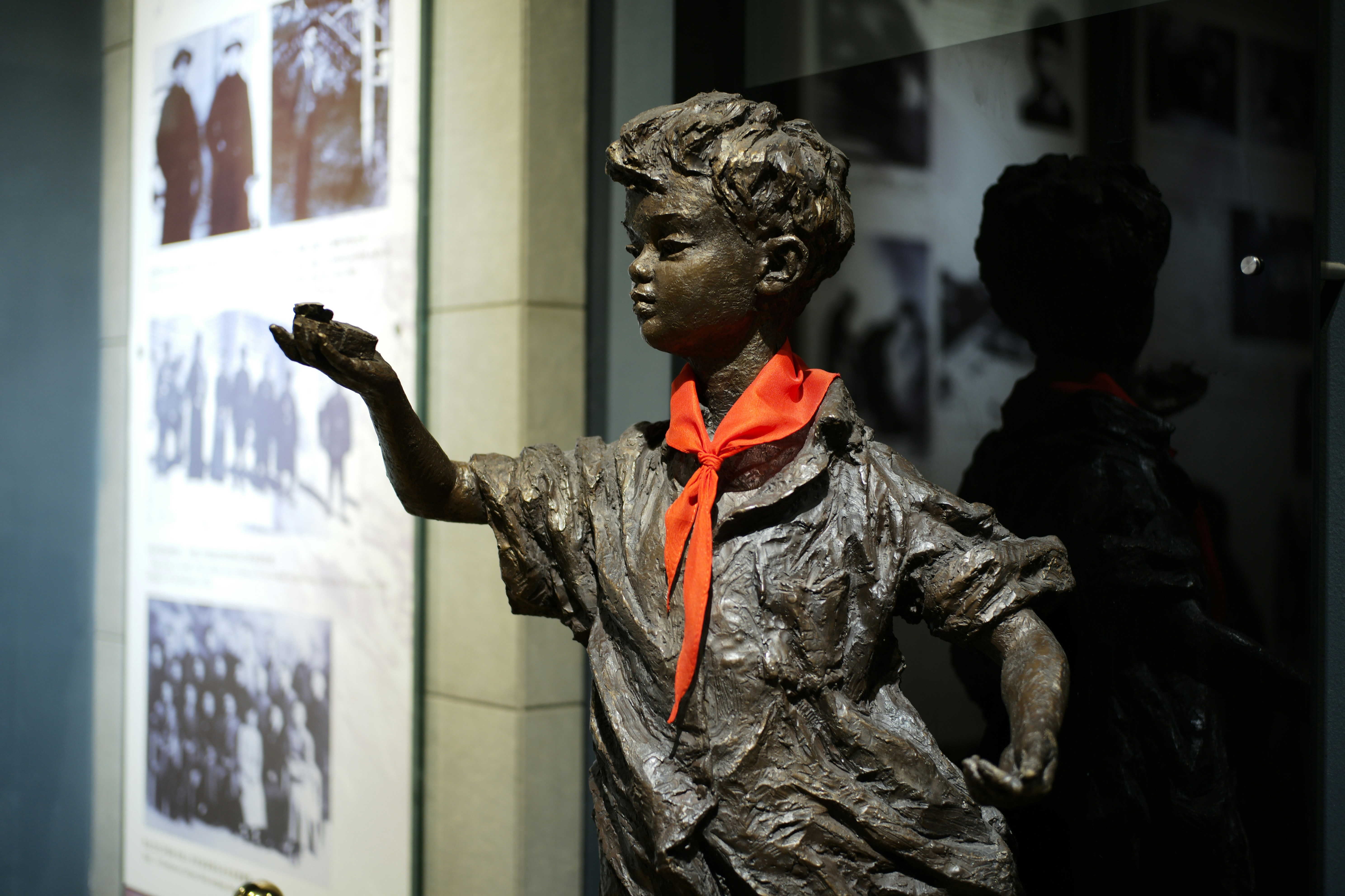 Bronze Boy with an Orange Scarf Reaching Out in a Museum Gallery