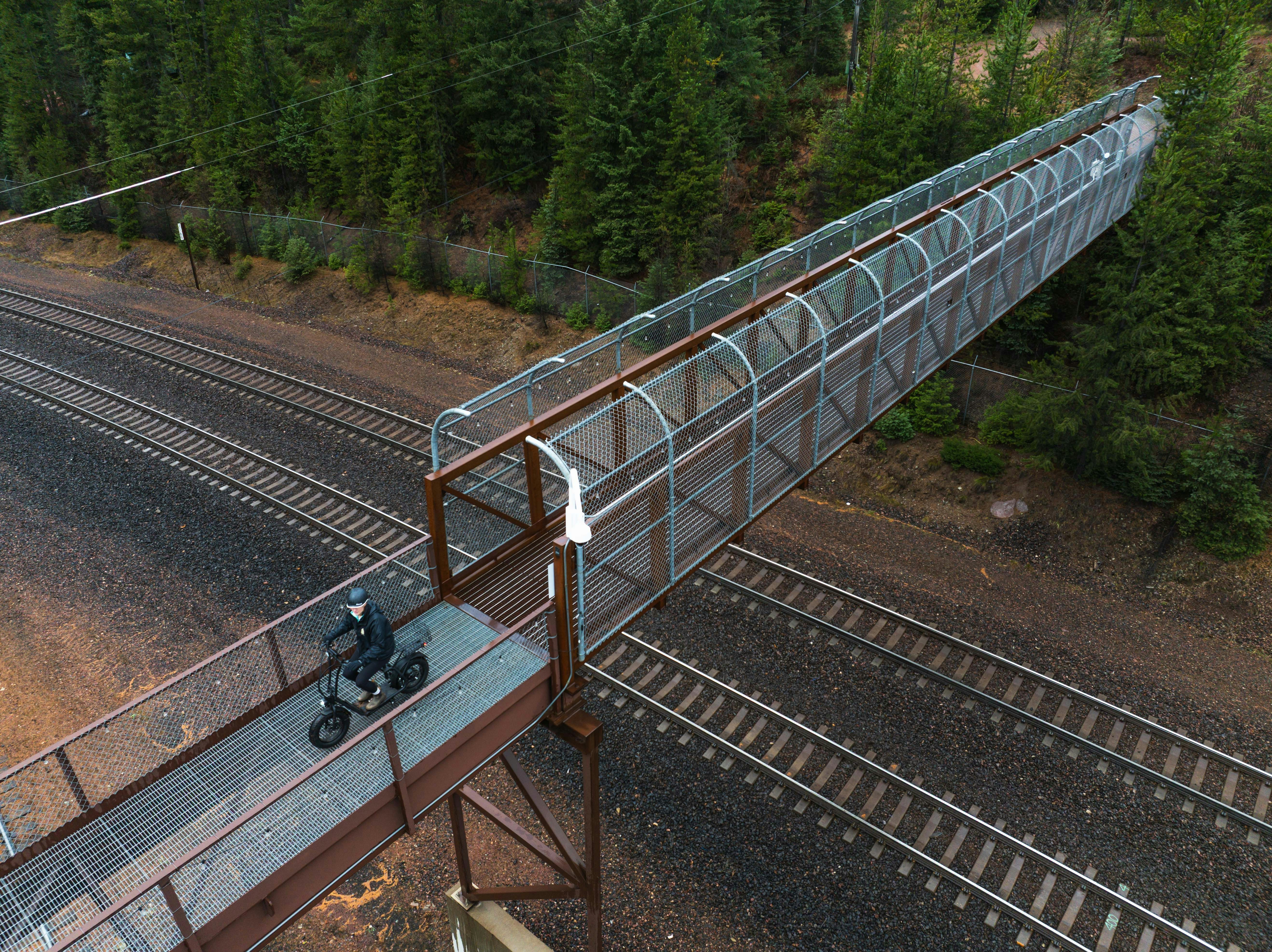 Rider on a Narrow Skywalk Above the Rails