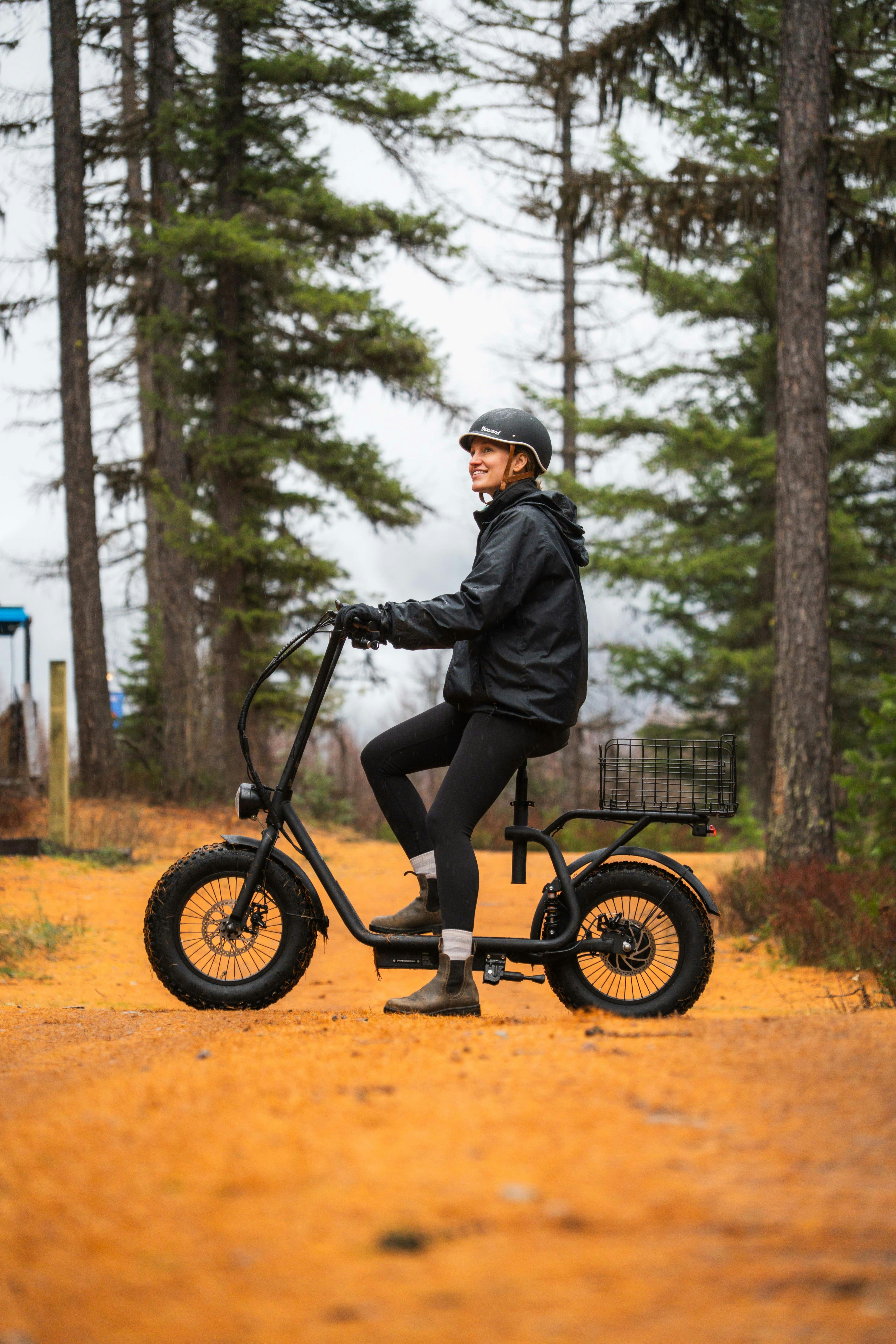 Trailbound in Orange Pines: A rider on a compact e-scooter navigates a forest path