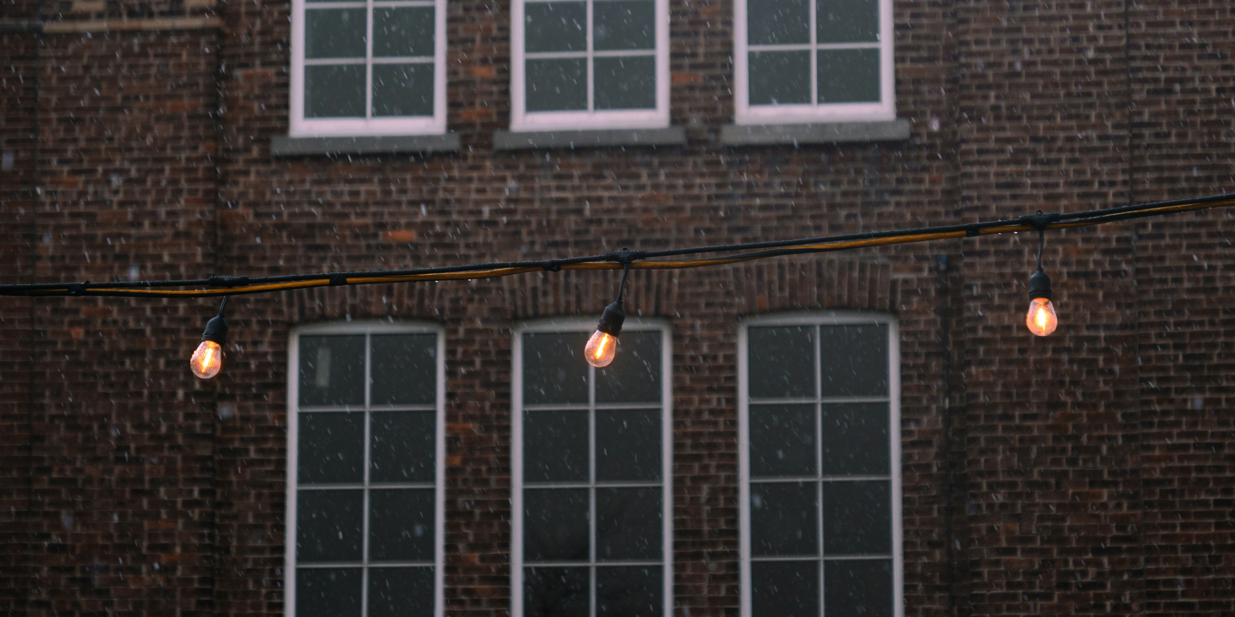 Overhead Edison Bulbs Span a Brick Facade at Dusk