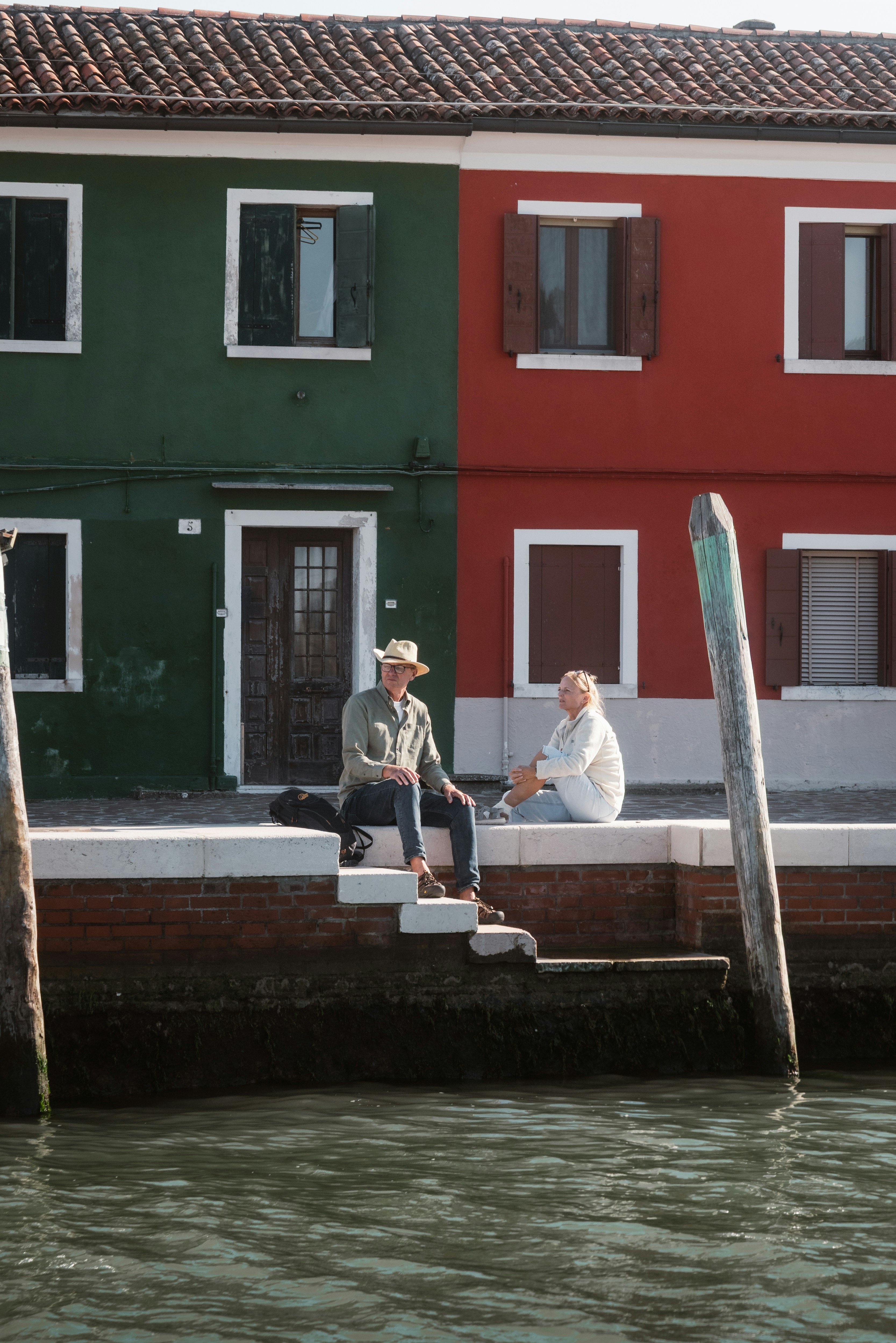 Conversation by the Canal: Two Figures at Color-Washed Facades