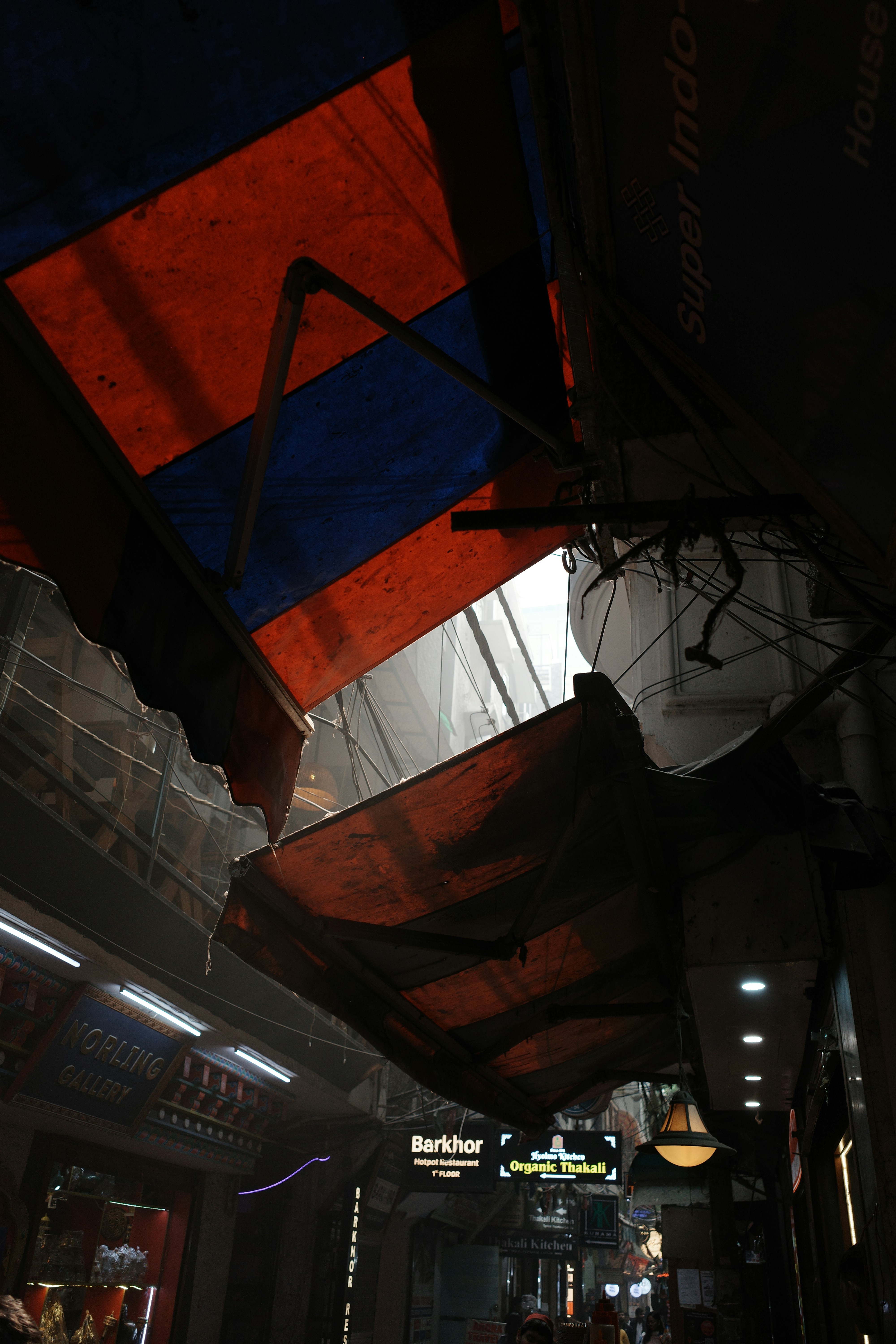 Neon and Rust: Canopies Loom Over a Narrow Night Market Alley