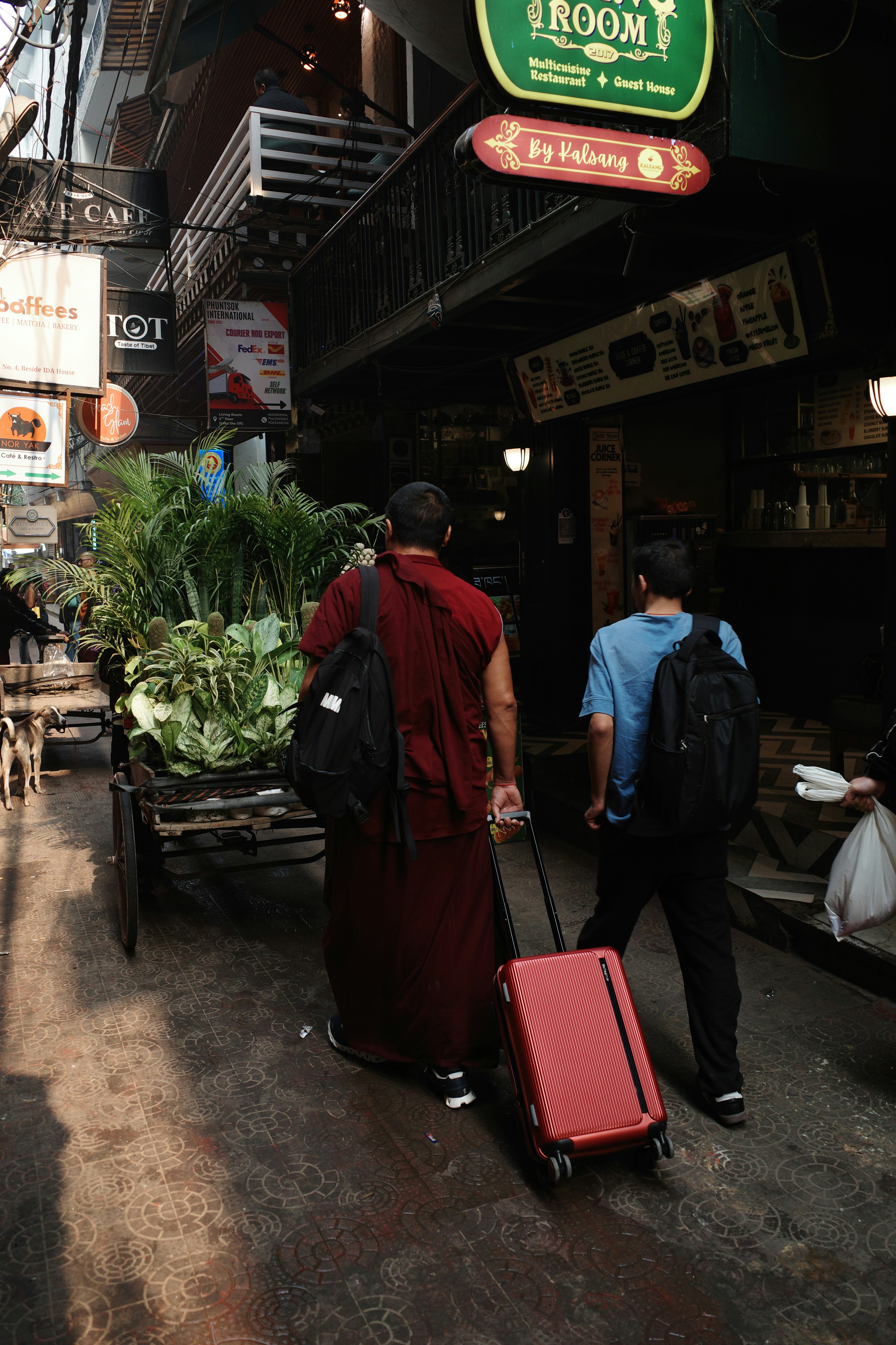 Neon Alley Companions: A Monk, a Traveler, and a Red Suitcase