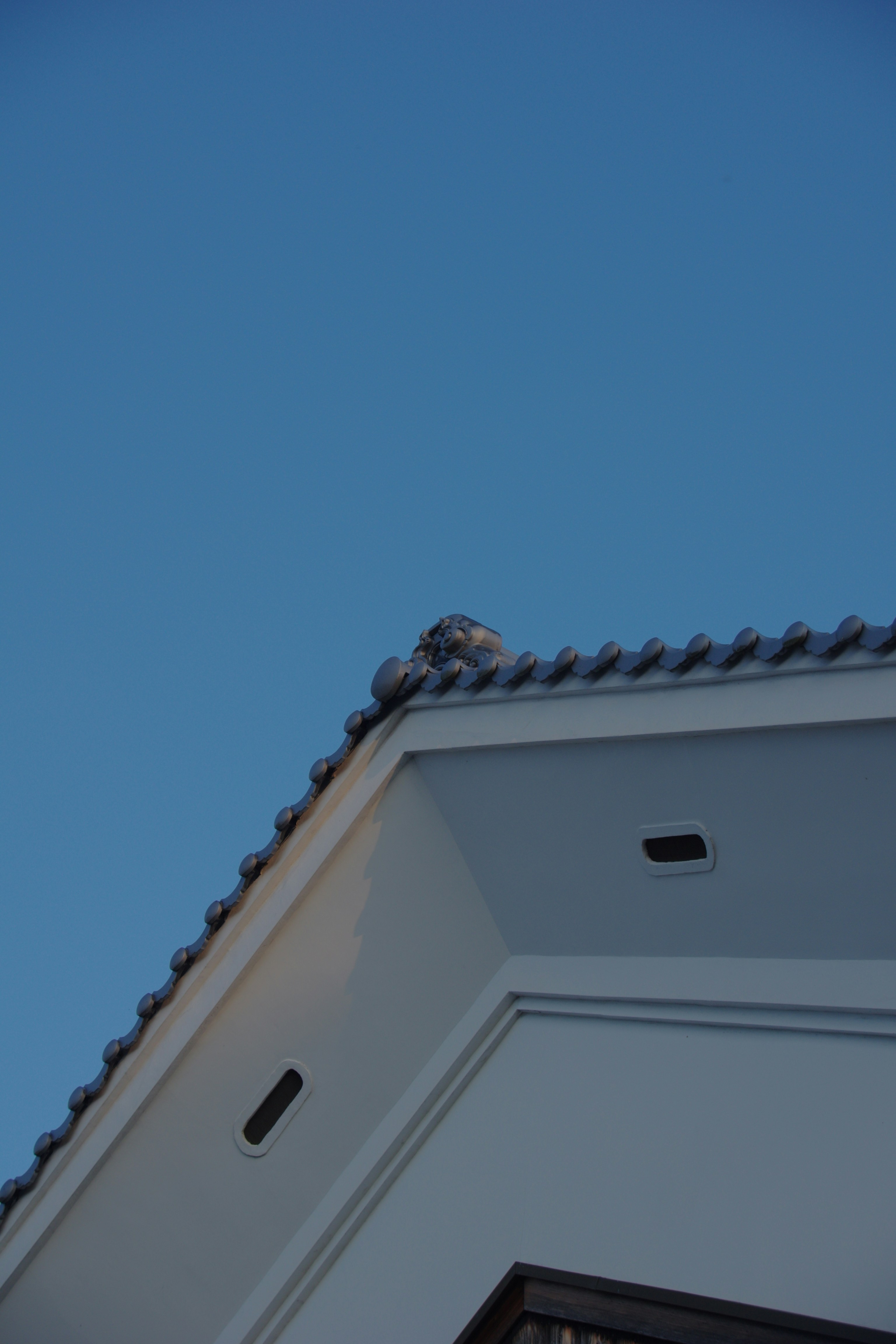 Diagonal Quiet: The Corner of a White Facade Against a Clear Blue Sky
