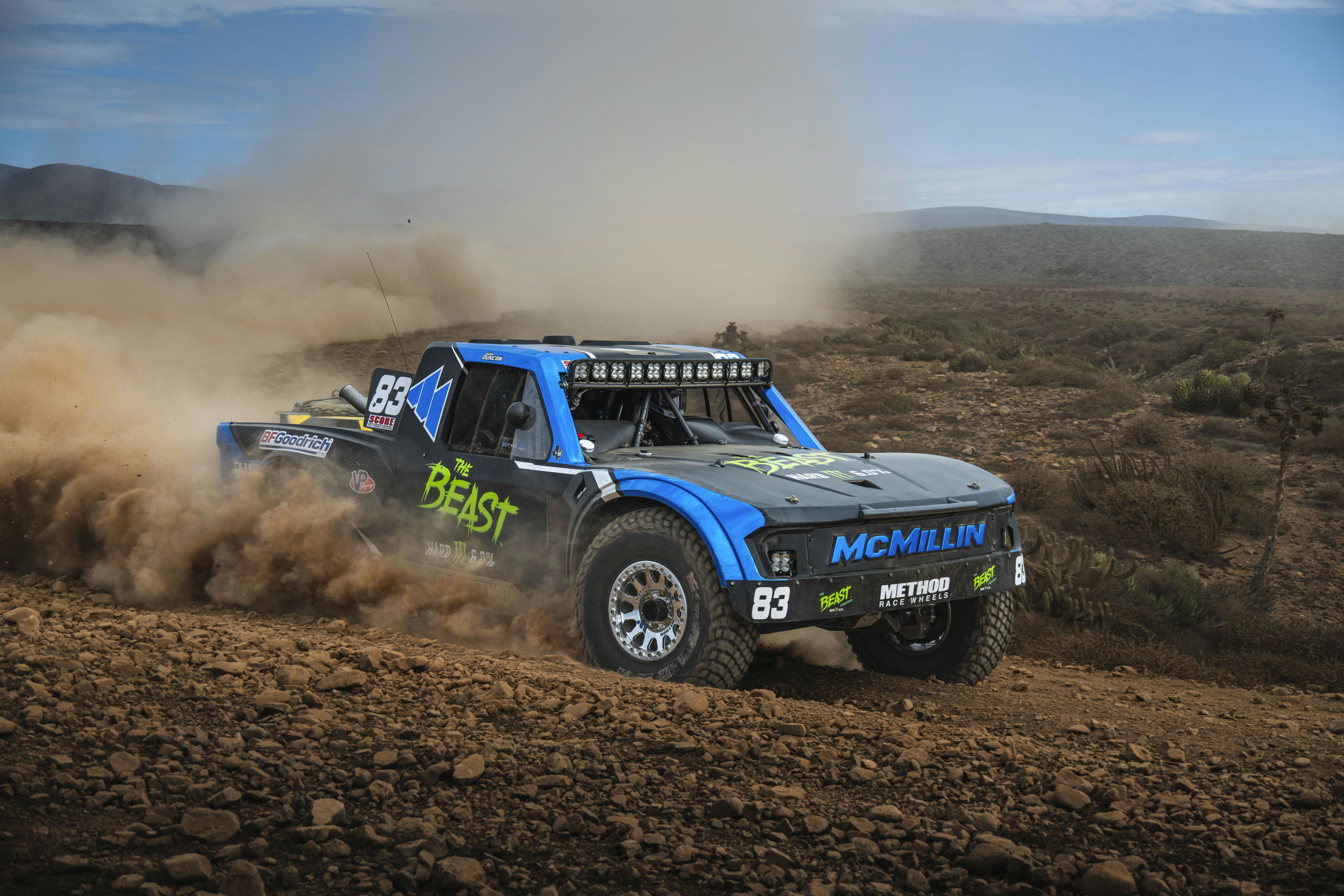 A blue off-road racing truck kicking up dust photo – Free Travel Image ...