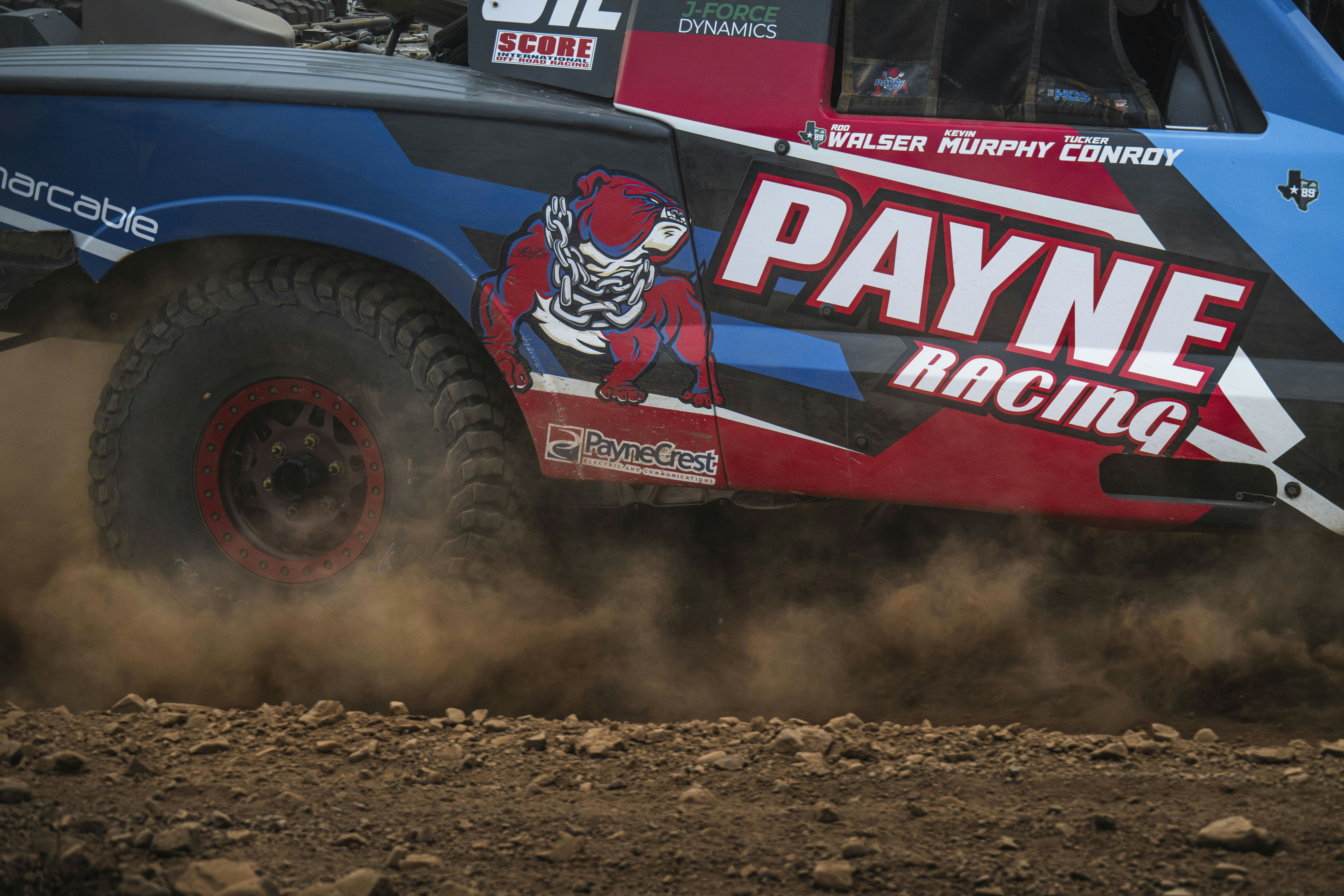 Payne Racing's Blue-and-Red Sprint Car Carves a Dusty Arc on a Muddy Dirt Track