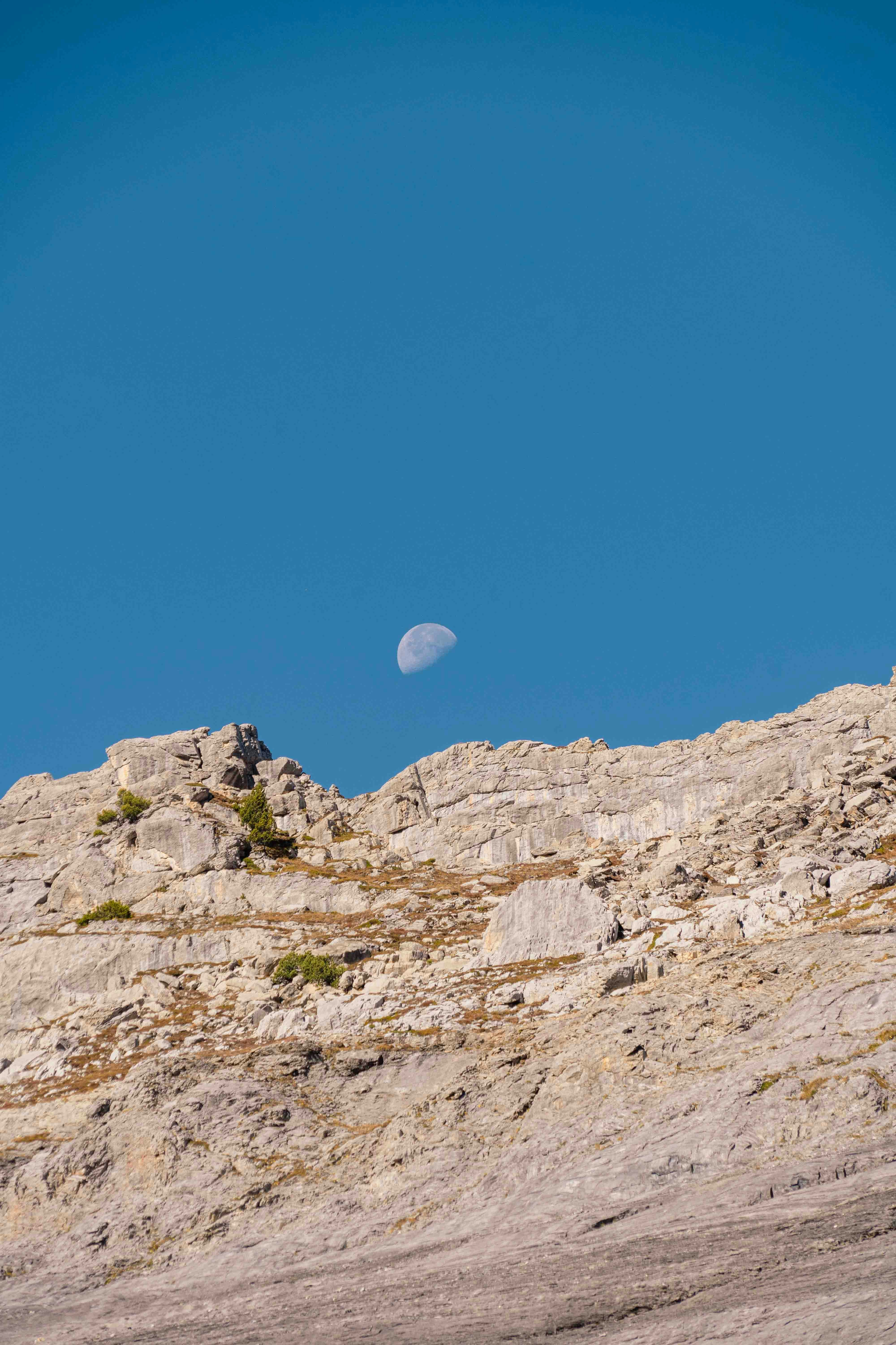 Moon over a limestone ridge under a cobalt sky