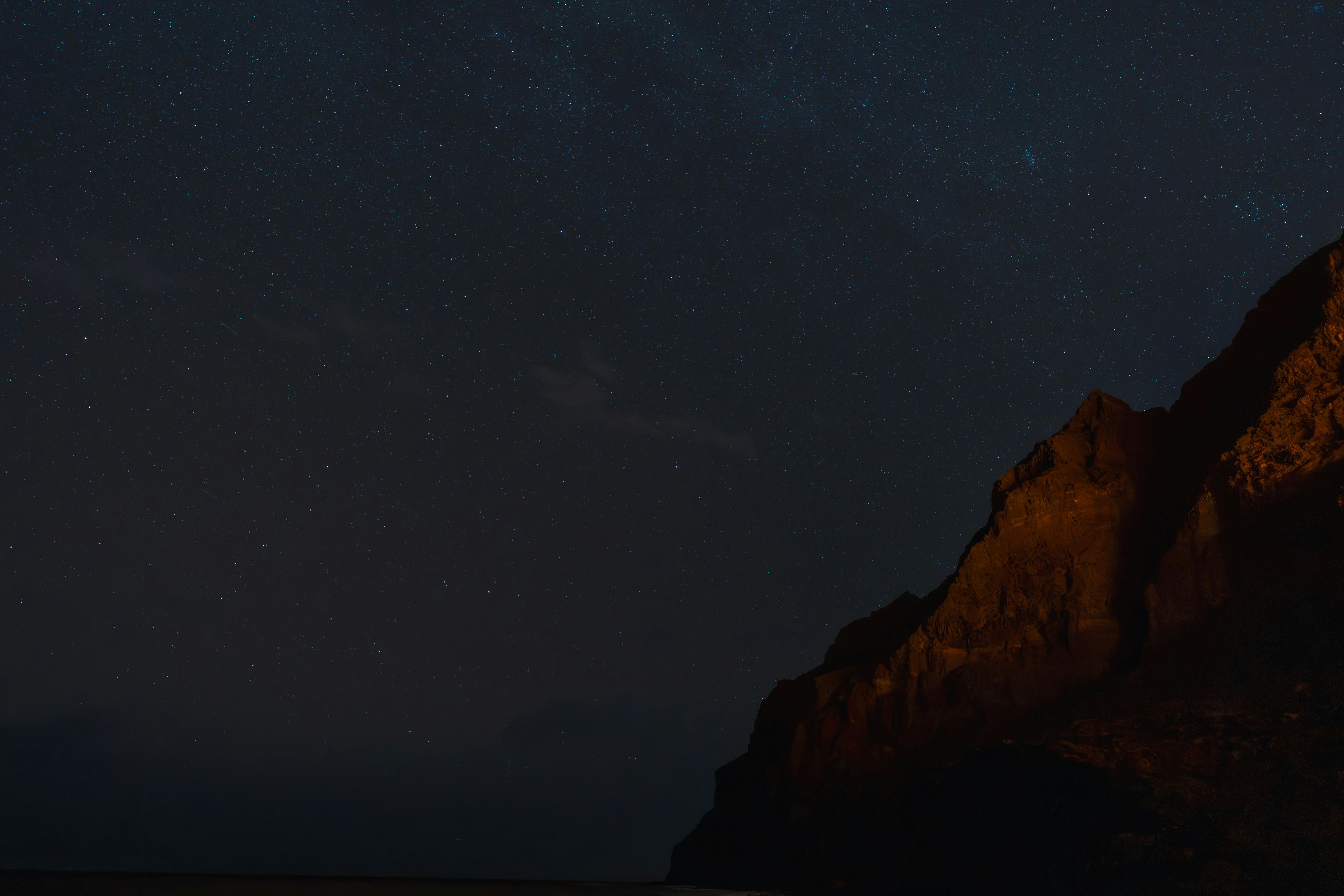Starfield Over the Ridge: Nightscape with a Fire-Tinged Cliff