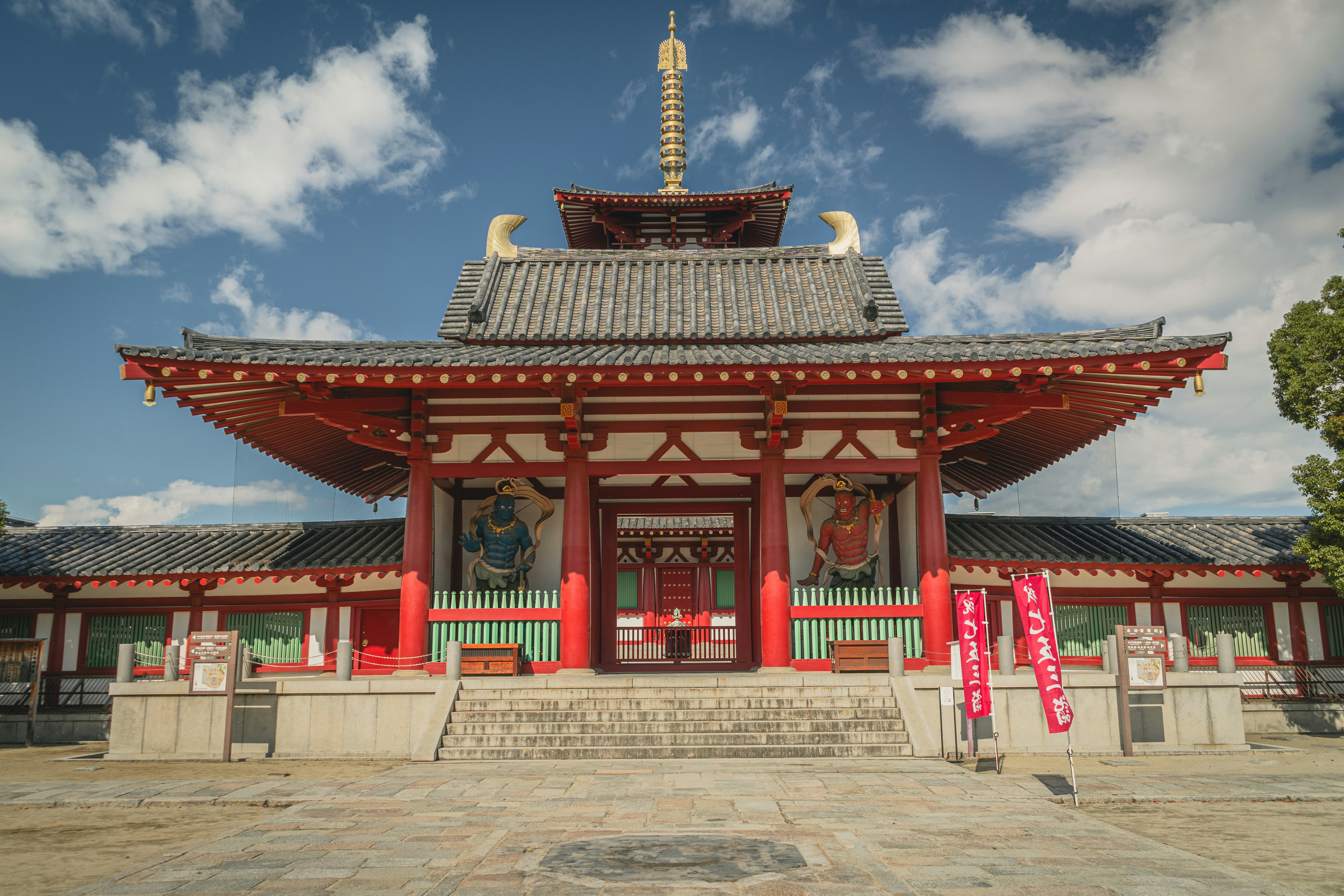 Two Nio guardian statues - Agyo (red, with open mouth) and Ungyo (blue, with closed mouth) - stand watch at the entrance of Shitennoji Temple in Osaka. These fierce protector deities represent traditional Buddhist symbolism and Japanese temple art.