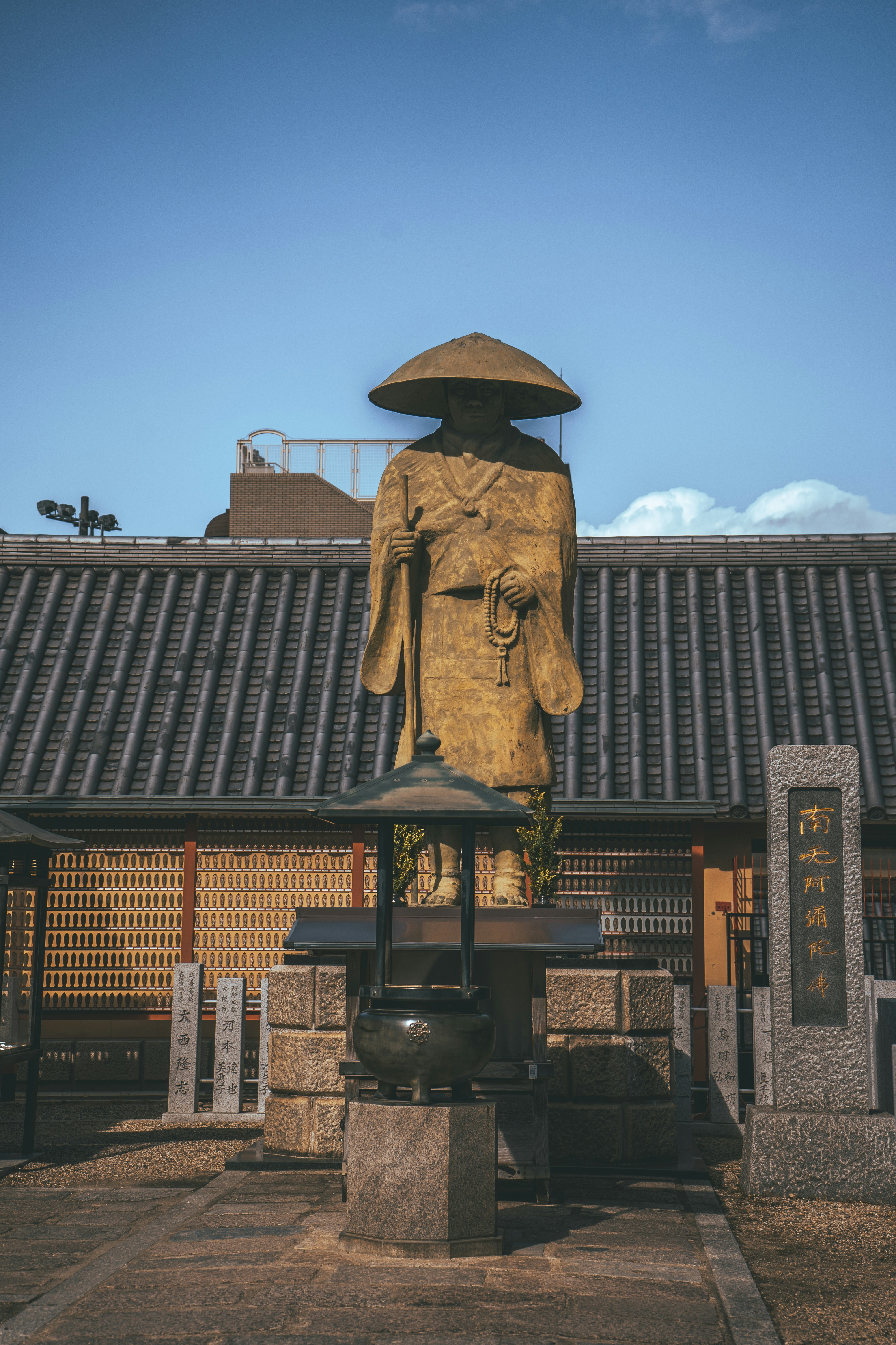 A stone statue of a Buddhist monk in the grounds of Shitennoji Temple in Osaka. The sculpture conveys tranquility and spiritual depth, blending harmoniously with the atmosphere of one of Japan's oldest Buddhist temples.
