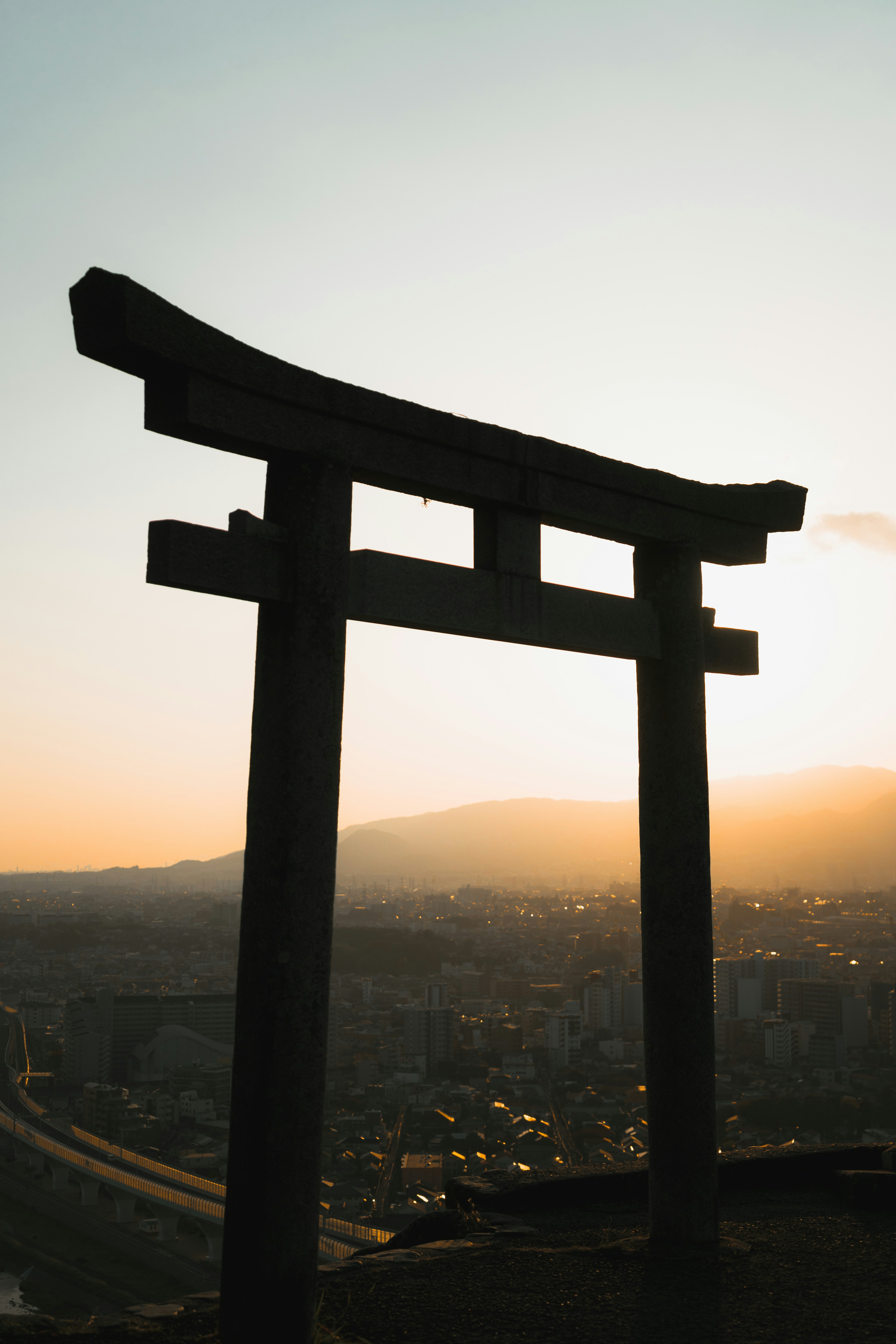 Torii Gate Silhouette at Sunset Over a Distant City