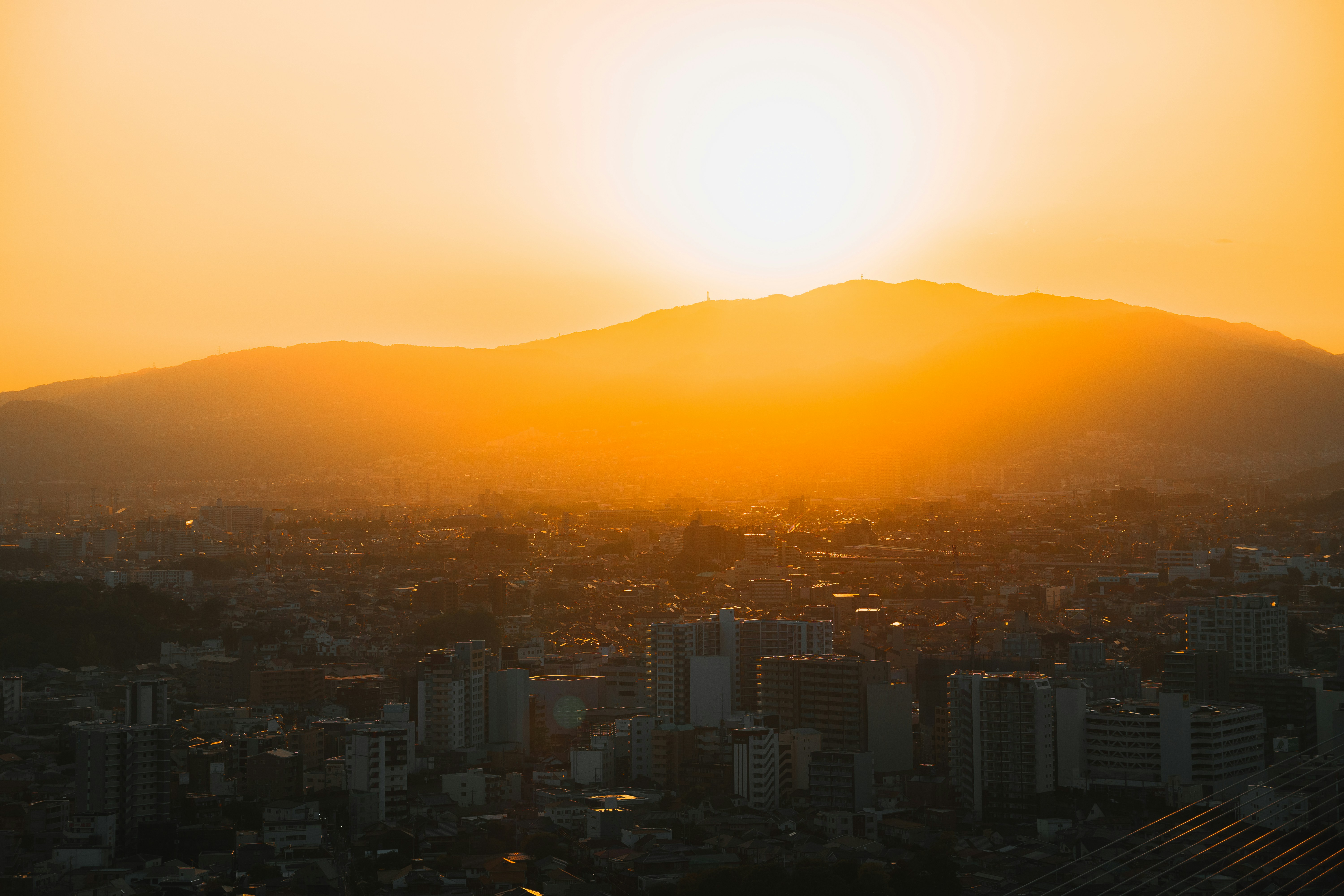 Golden sun setting behind hazy mountains over city. photo – Free Travel ...