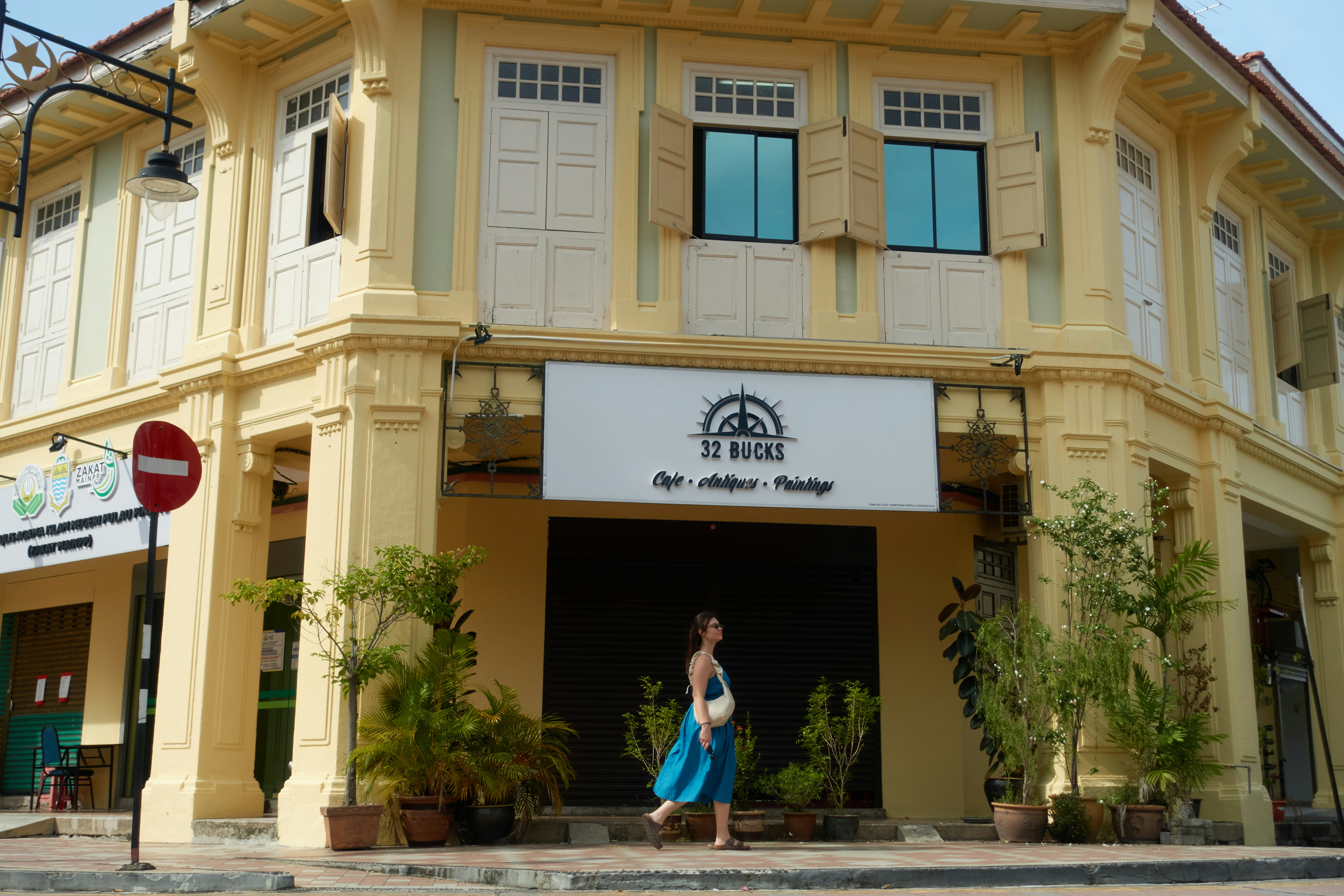 Blue Dress, Yellow Facade: A Quiet Moment by a Colonial Shopfront
