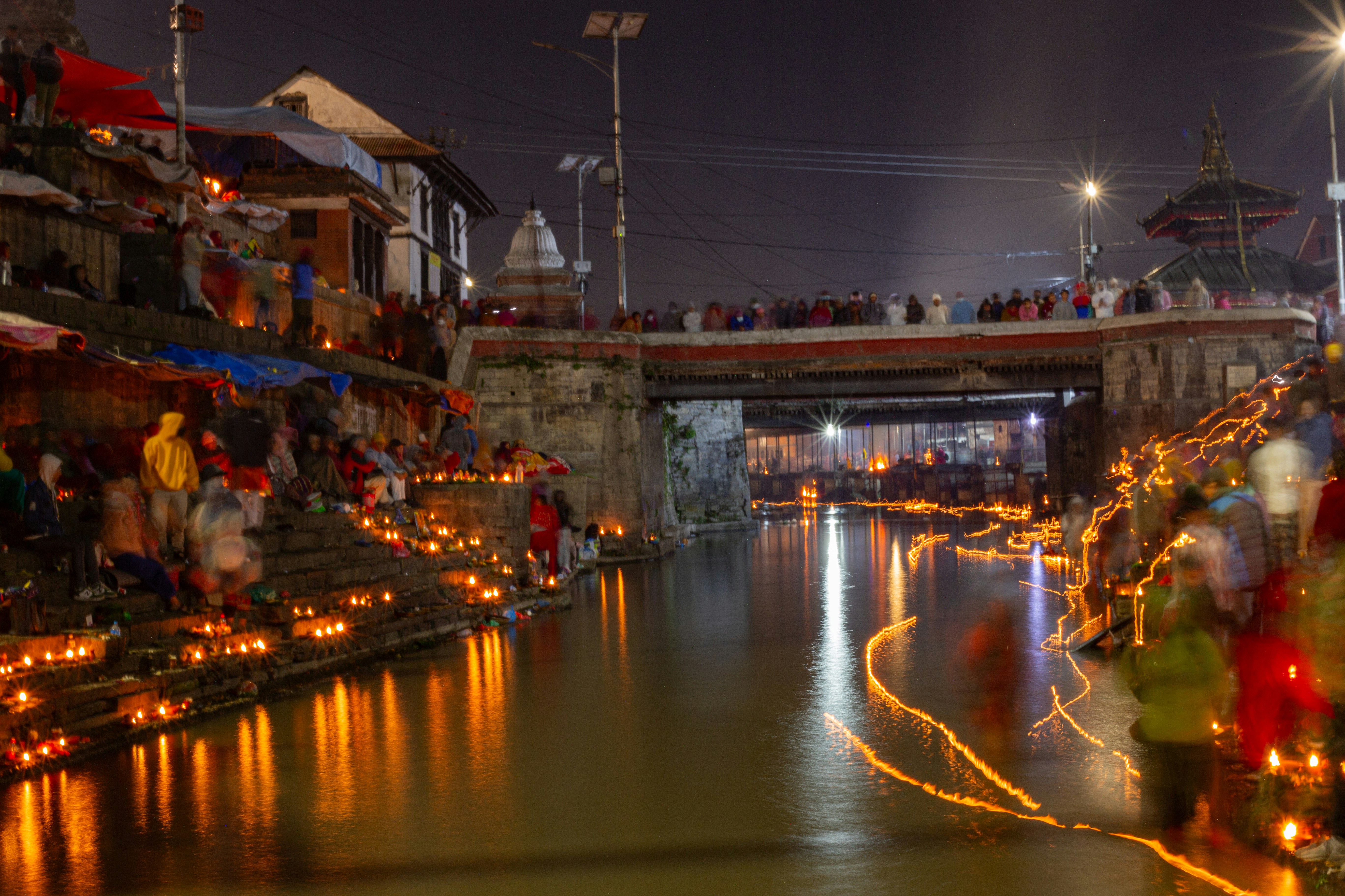 Ghat of Light: Candlelit River and a Bridge Framed by Reflections