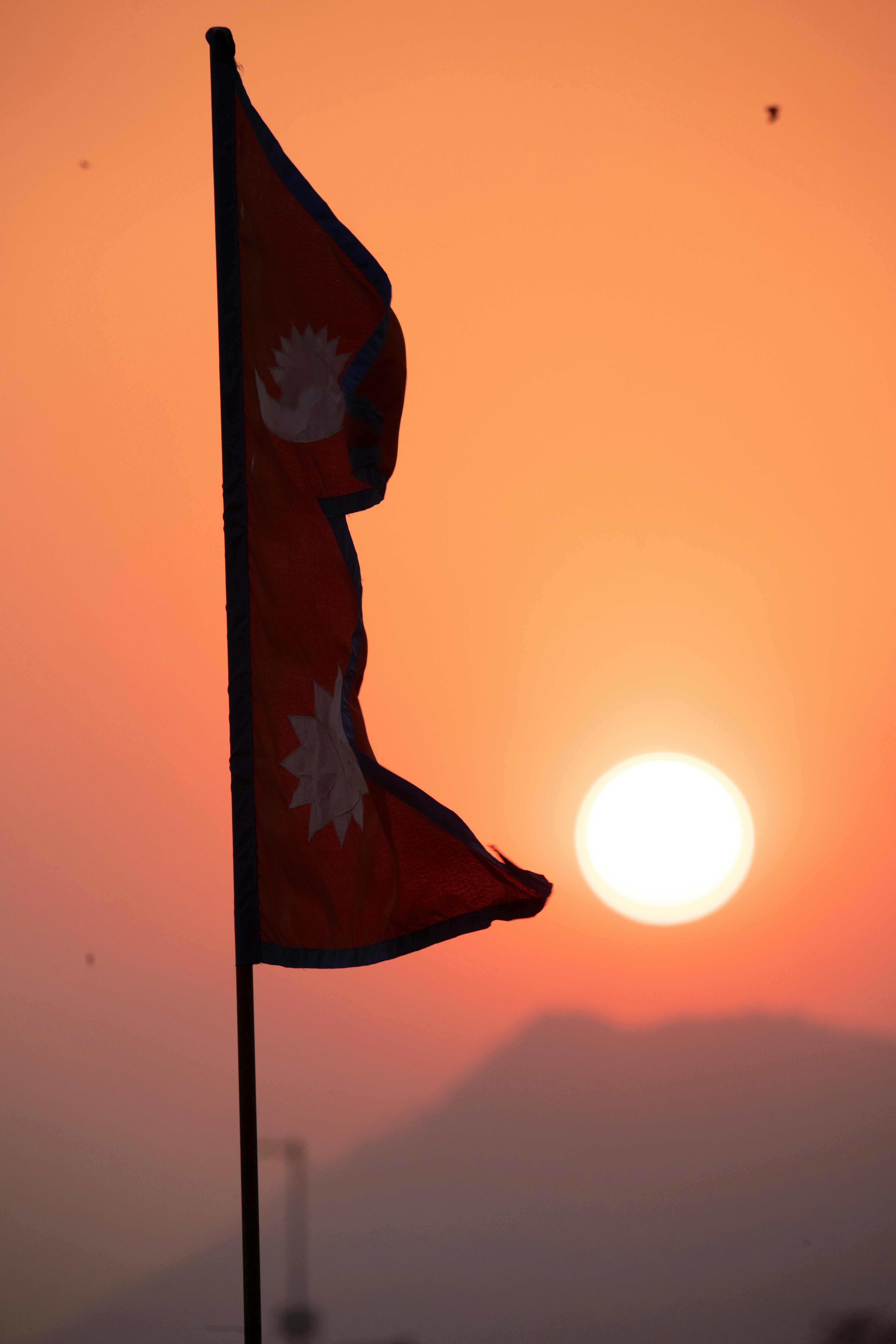 Flagpole at Sunset: A Lone Banner Stands Against a Molten Sky
