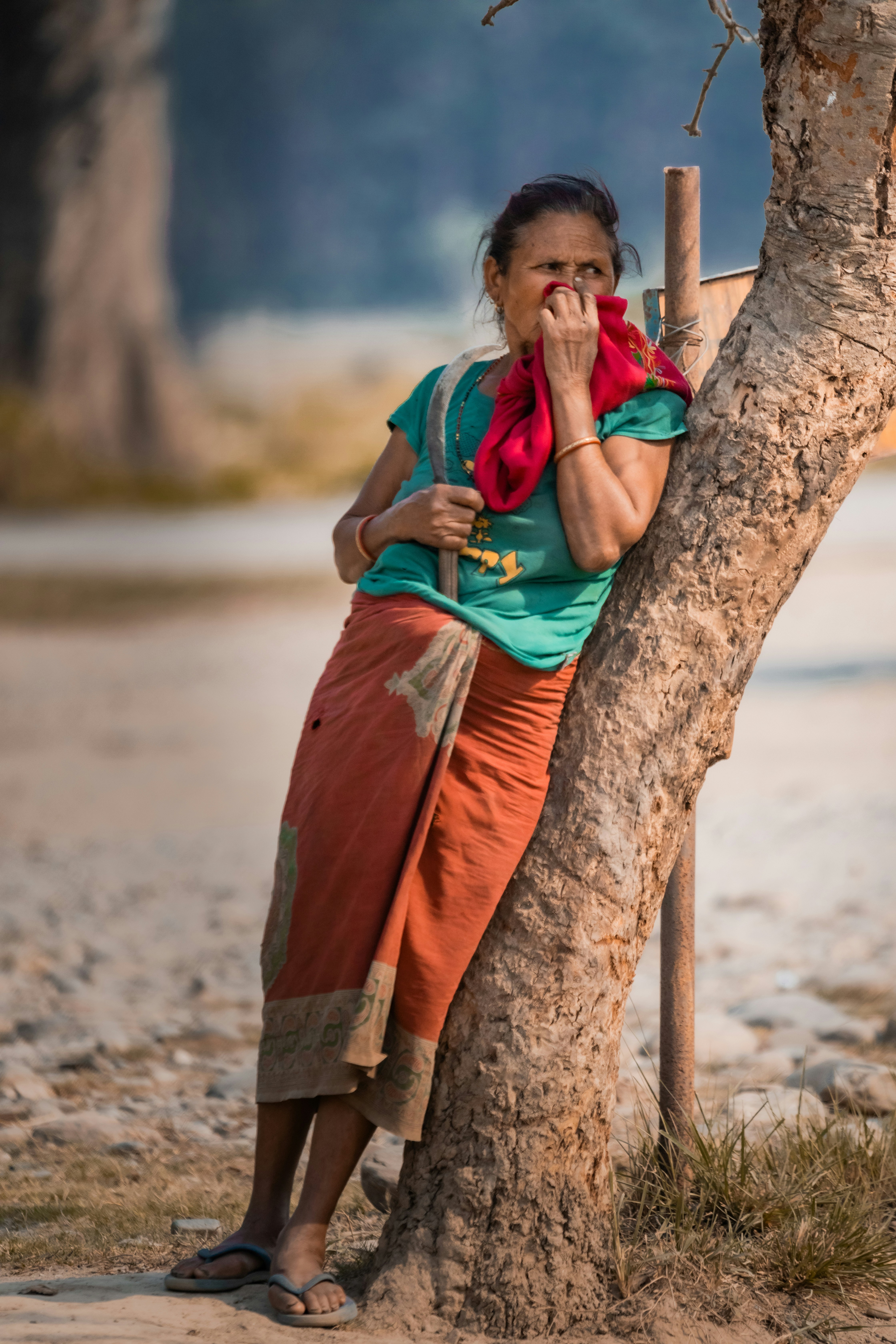 Quiet Resilience by the Tree: A Woman Pauses on a Sunlit Path