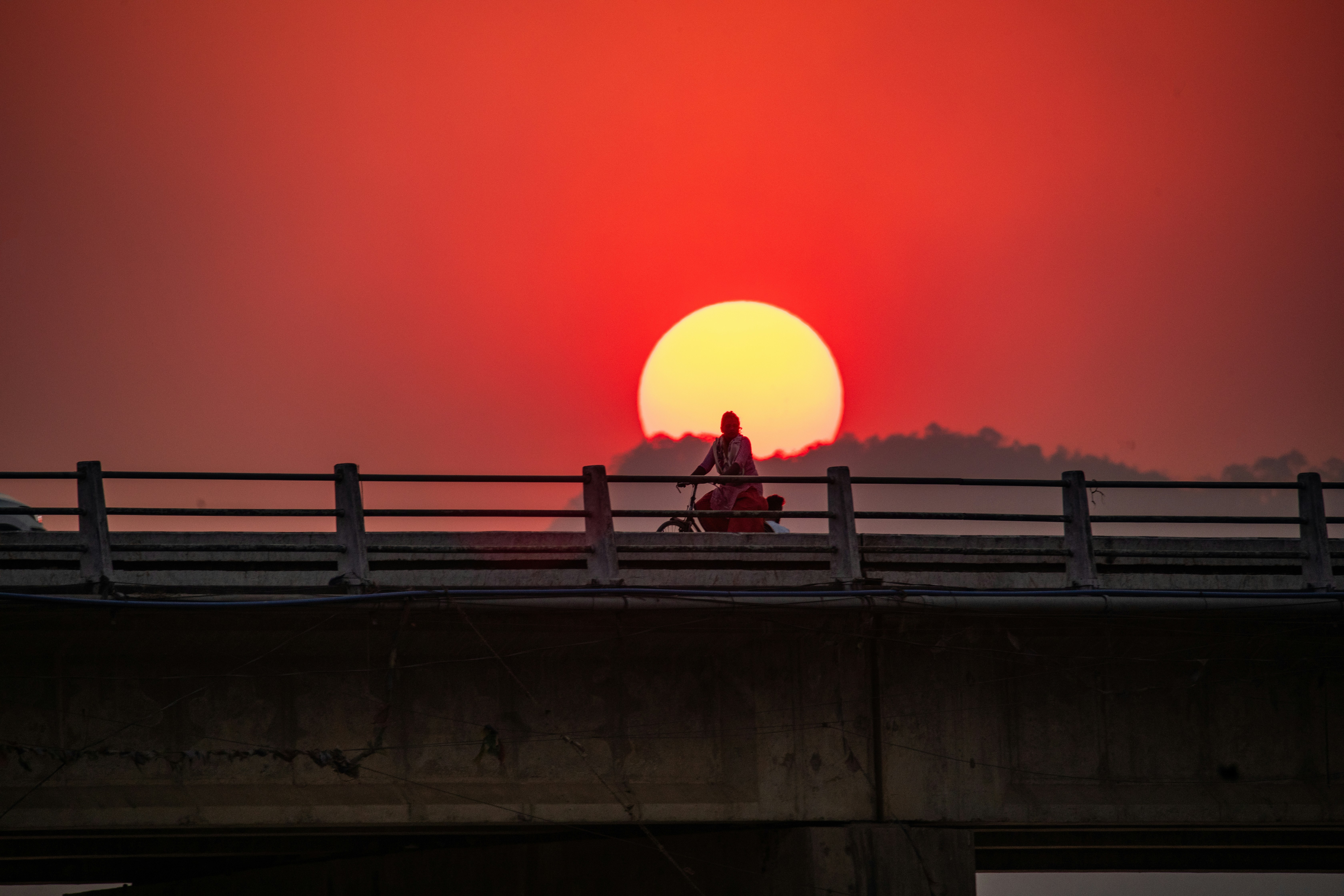 women riding bicycle at Narayani bridge with big sun in the background