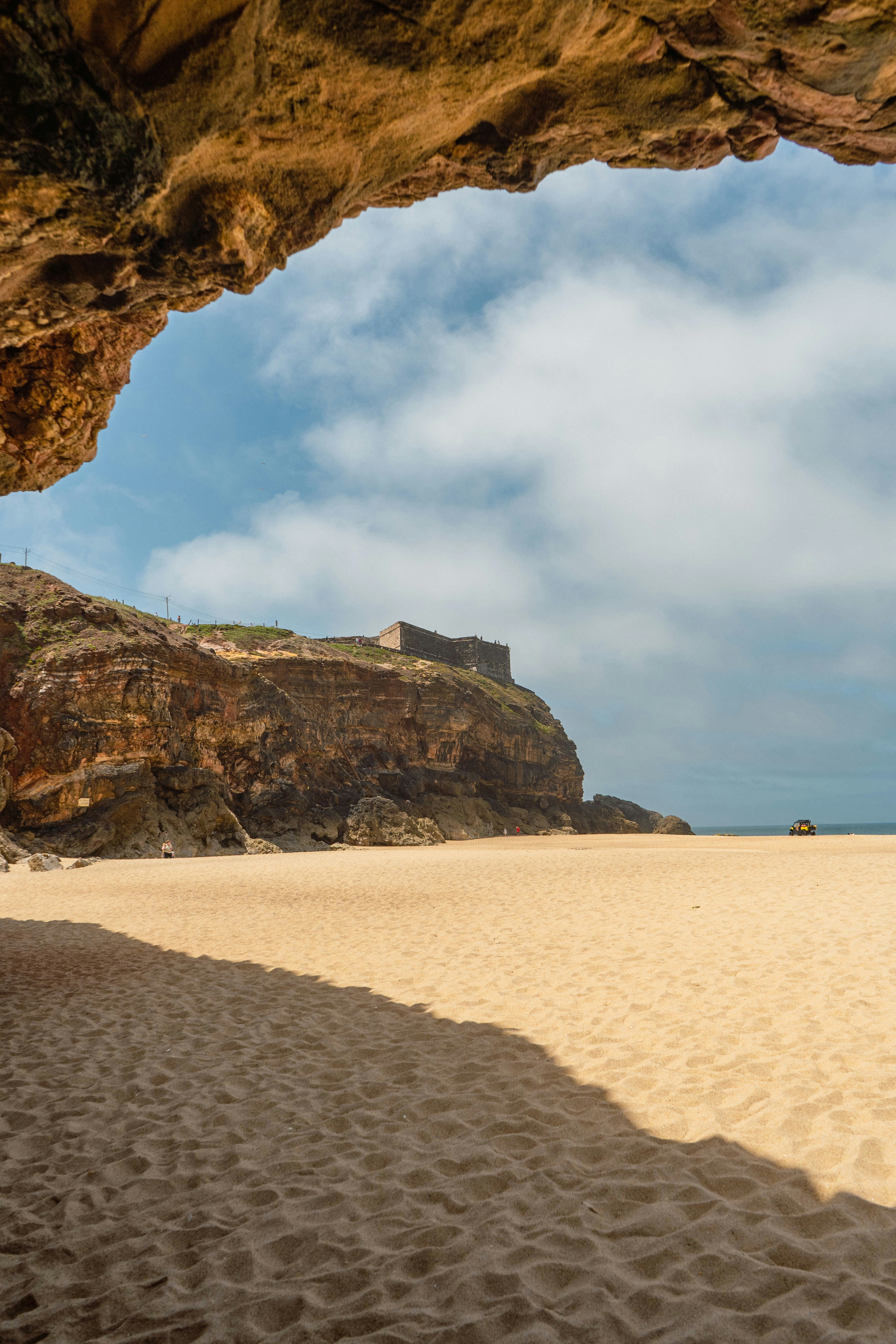 Fortress on the Cliff: A Sunlit Beach Framed by a Rugged Rock Arch
