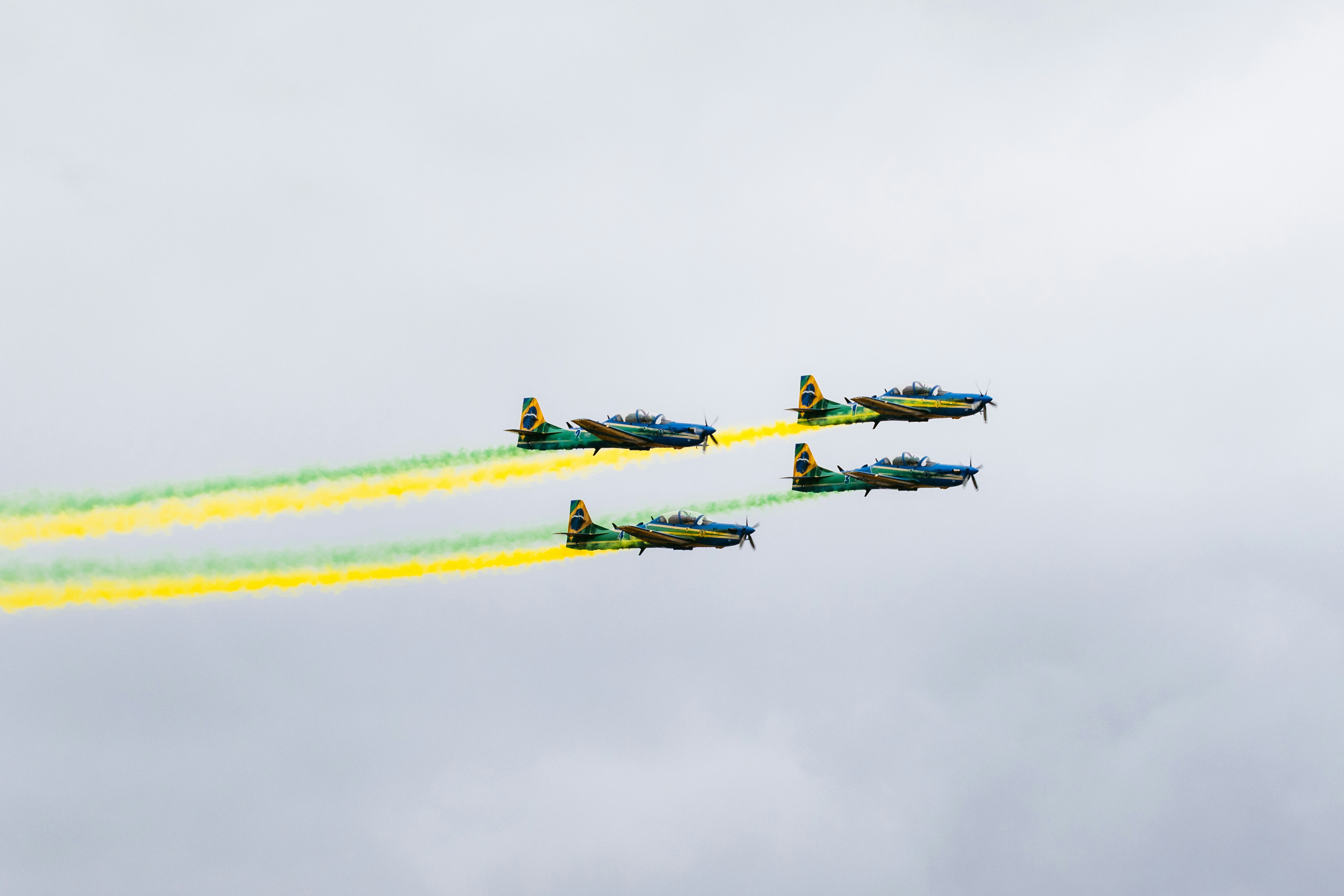 Formation in Color: Four Aerobatic Planes Leave Neon Trails Across a Pale Sky