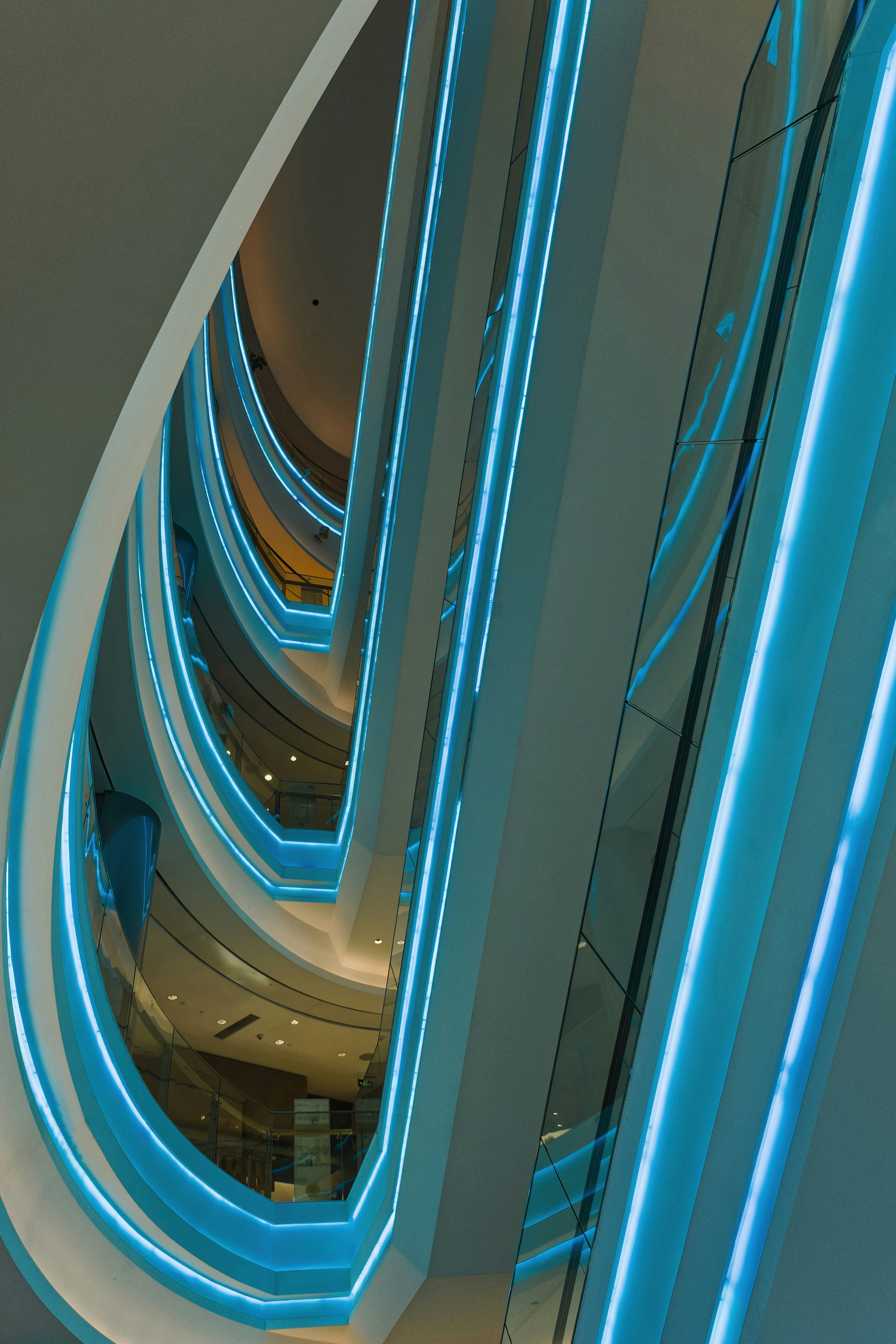 Unique architectural design featuring blue lights in a modern building interior - This scene showcases a modern building with striking architectural lines, highlighted by vibrant blue lighting. The open space creates a captivating view from above.