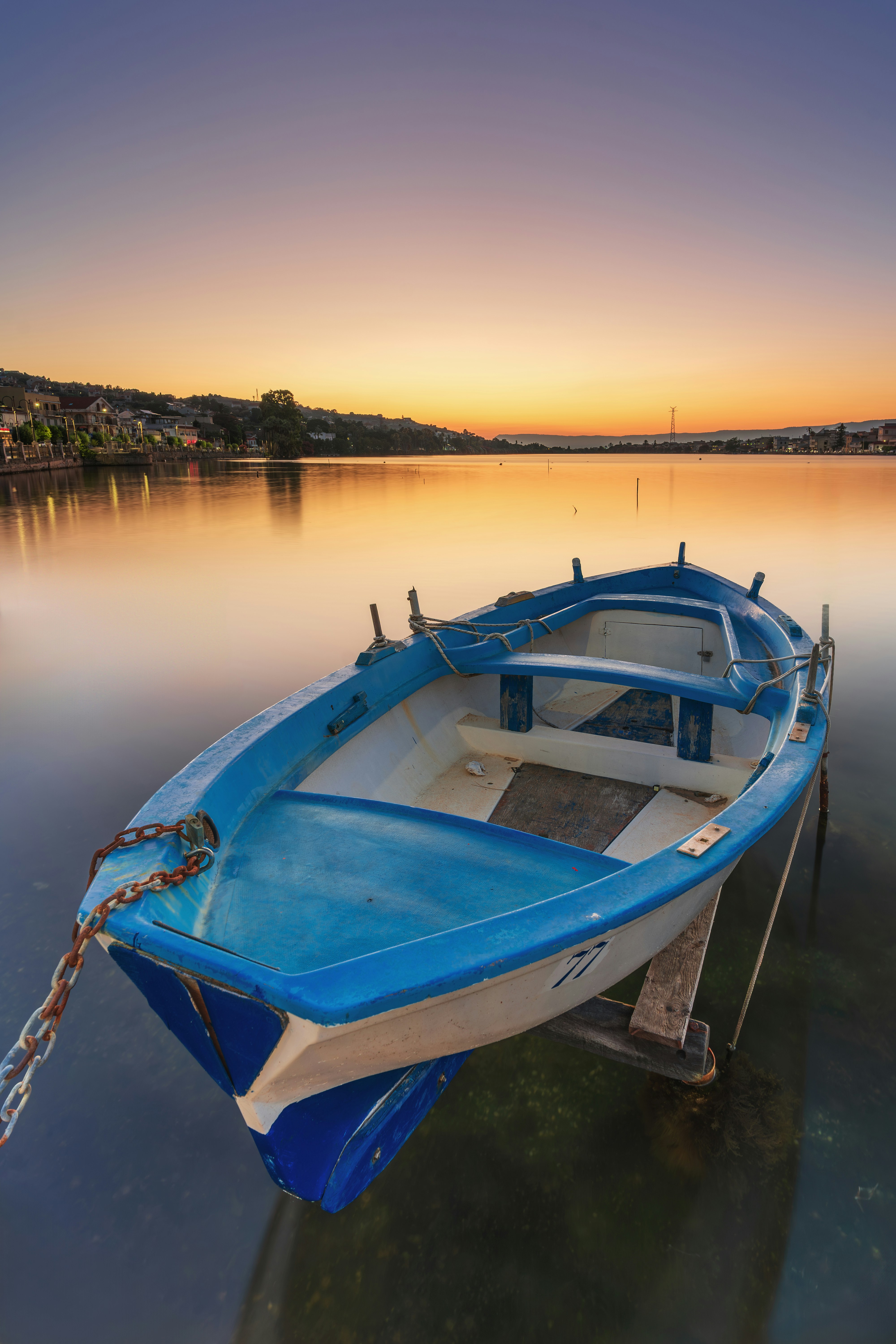 Dusk Harbor: A Blue Rowboat Resting at Sunset's Edge