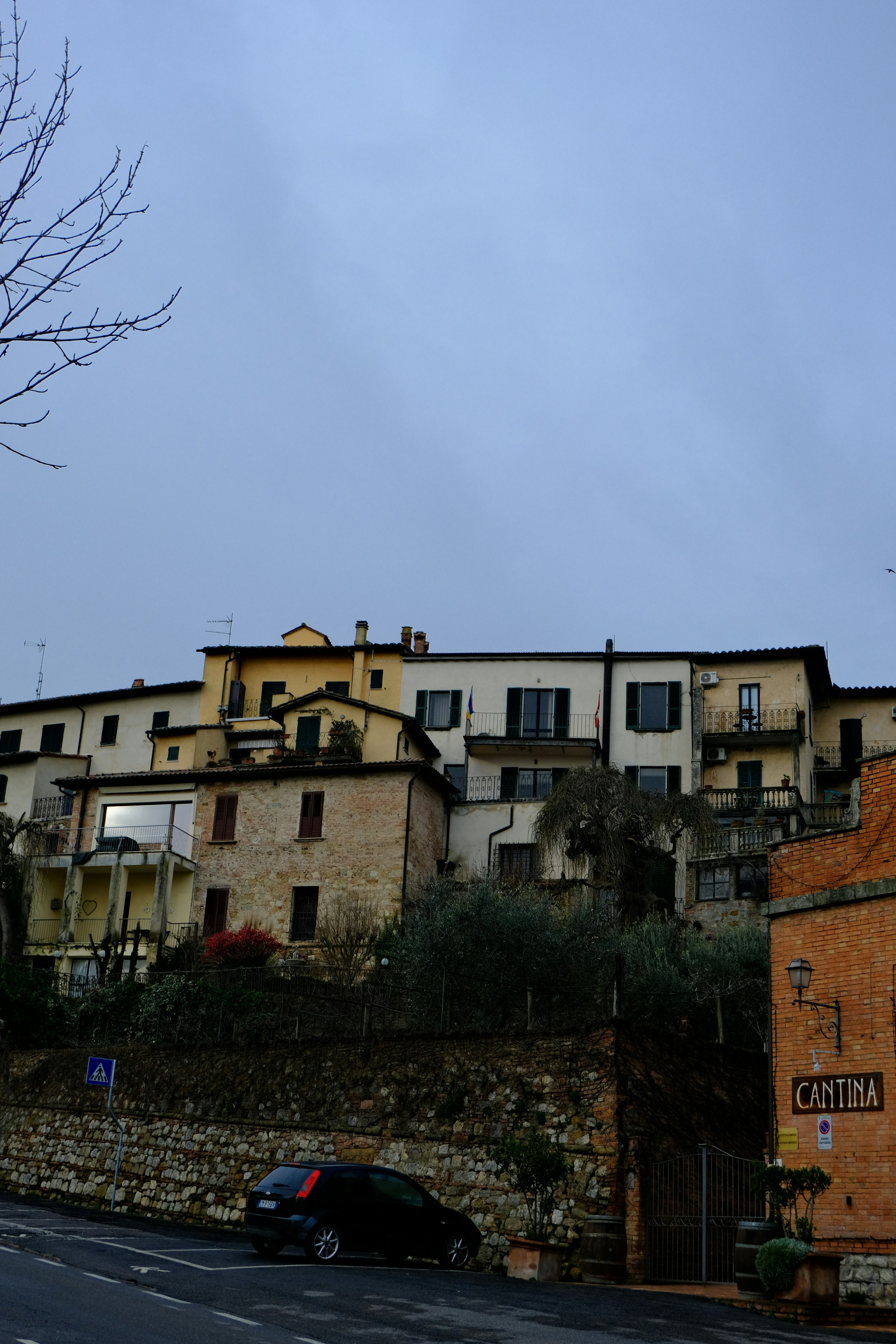Cantina on the Hill: Terraced Houses Crown a Quiet Hillside Under a Pale Blue Sky