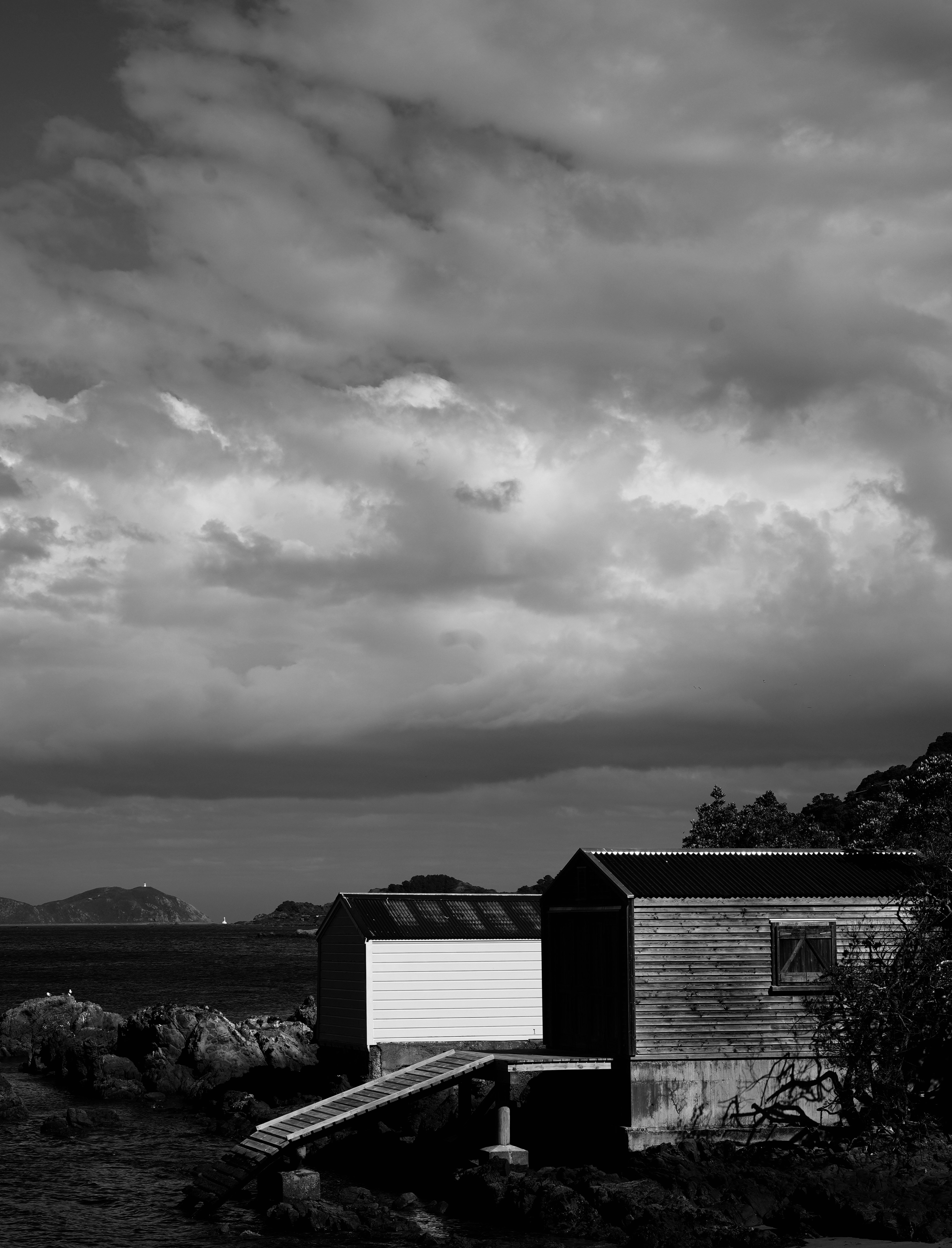Two Weathered Boathouses Quietly Guard the Rocky Shore