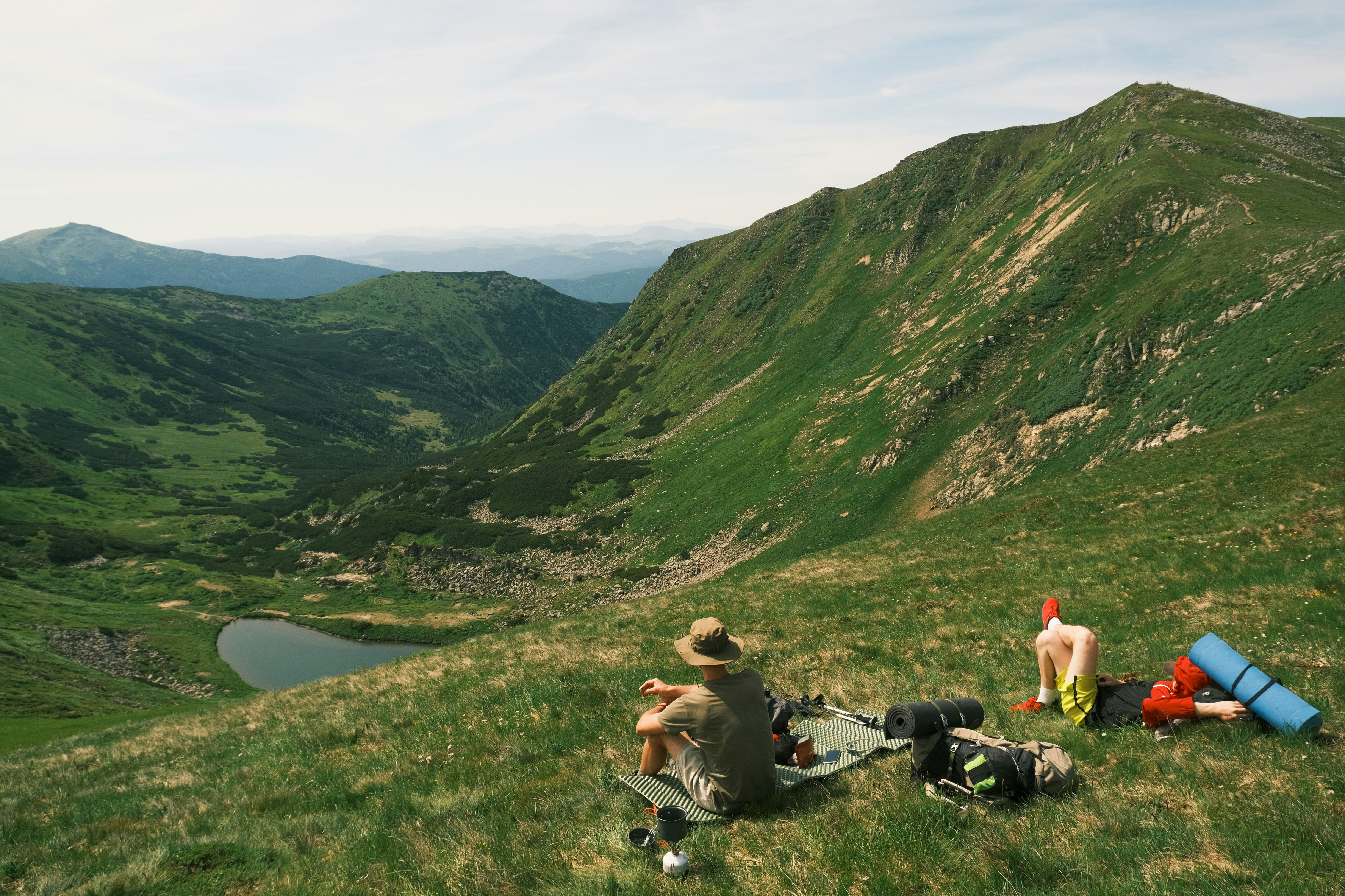 Verdant Ridge Pause: Hikers Rest Above a Quiet Alpine Lake