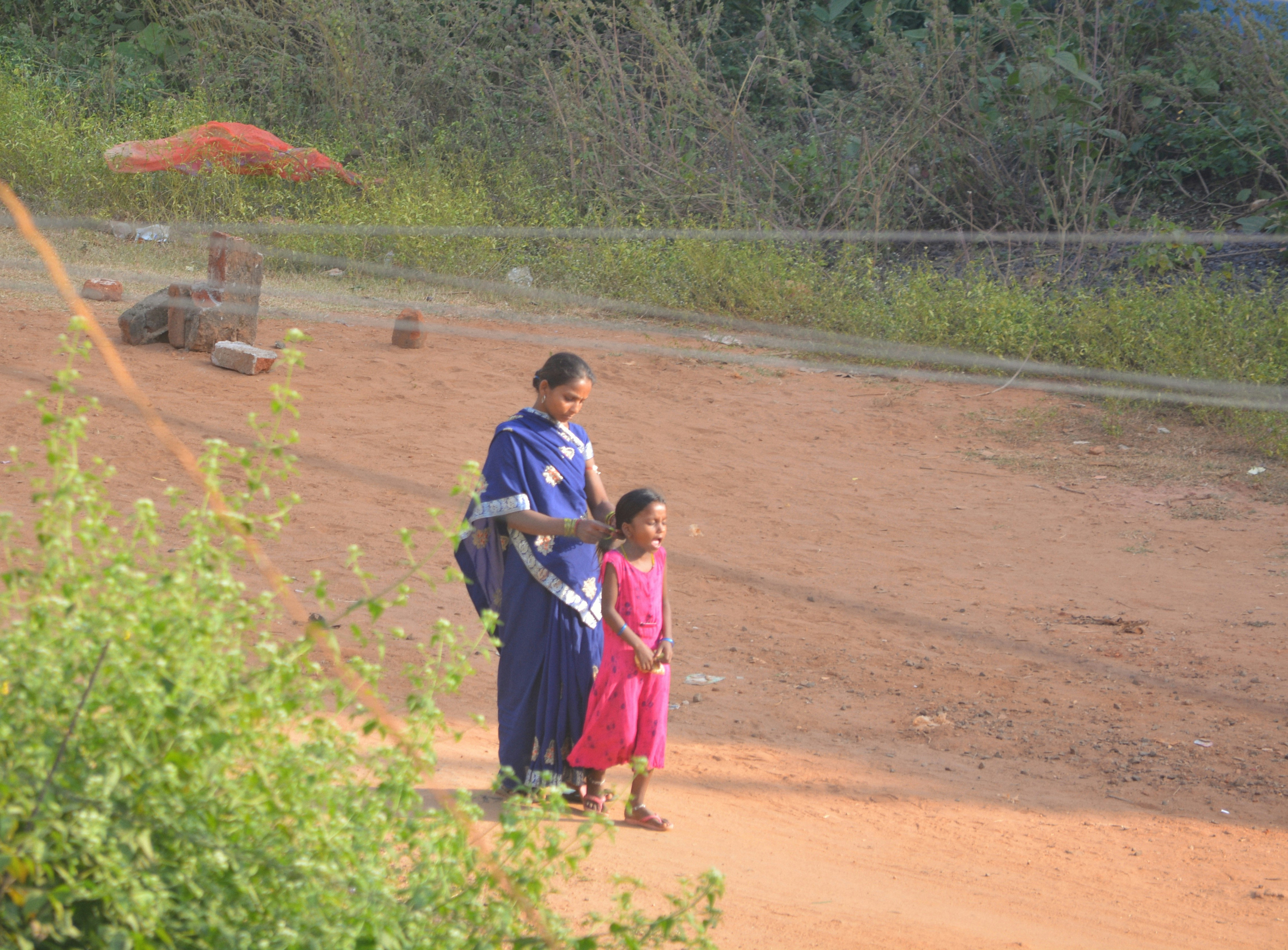 Dust Road Guardians: A Mother and Daughter Stand by the Road
