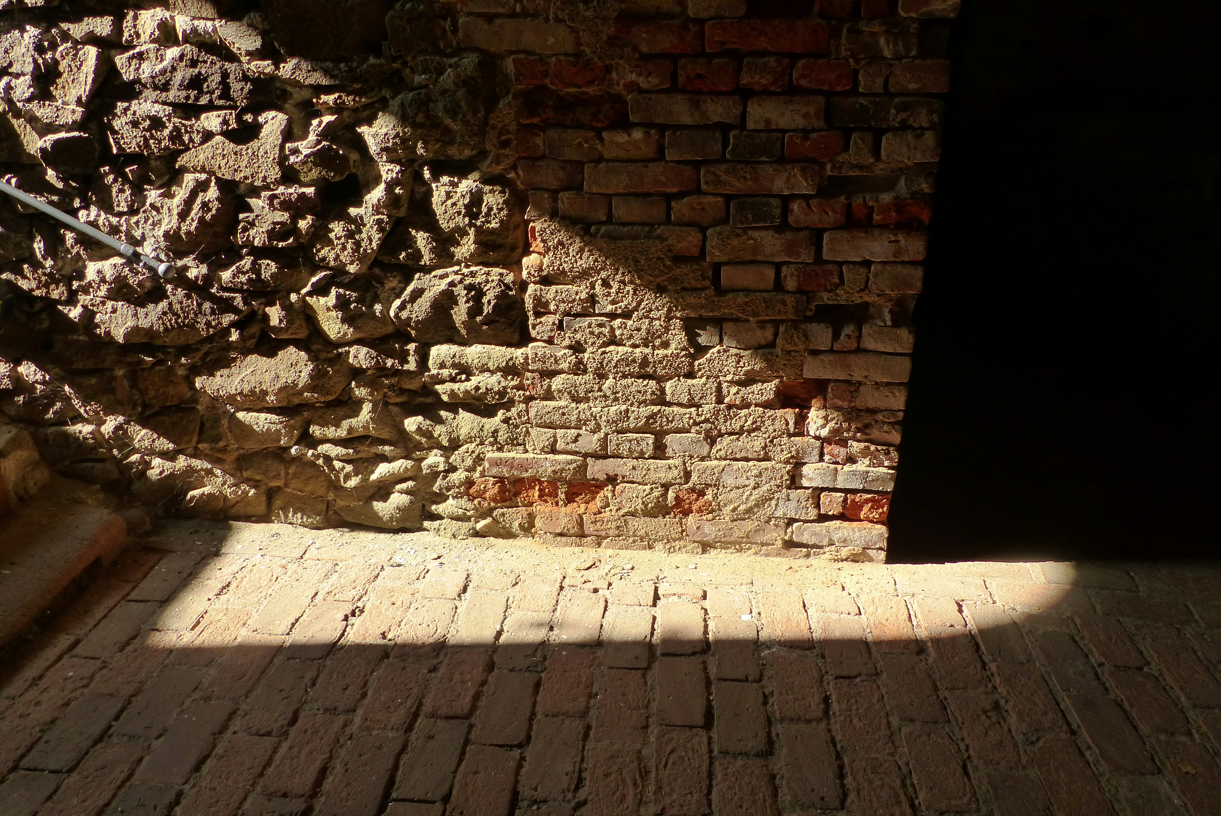 Sunlit Stripe Across Weathered Brick and Cobblestone