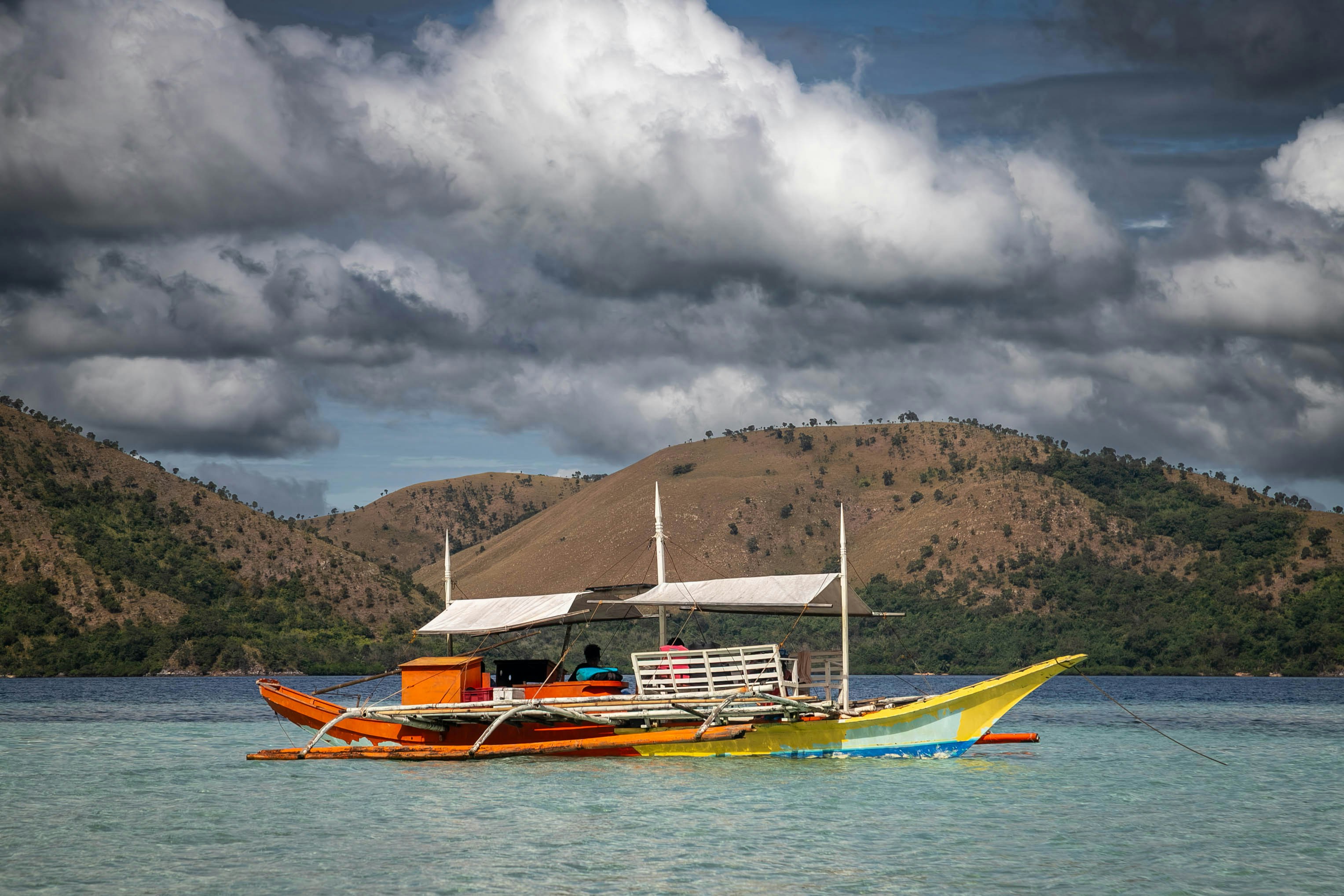 Rainbow Outrigger on Turquoise Seas under a Looming Cloudscape