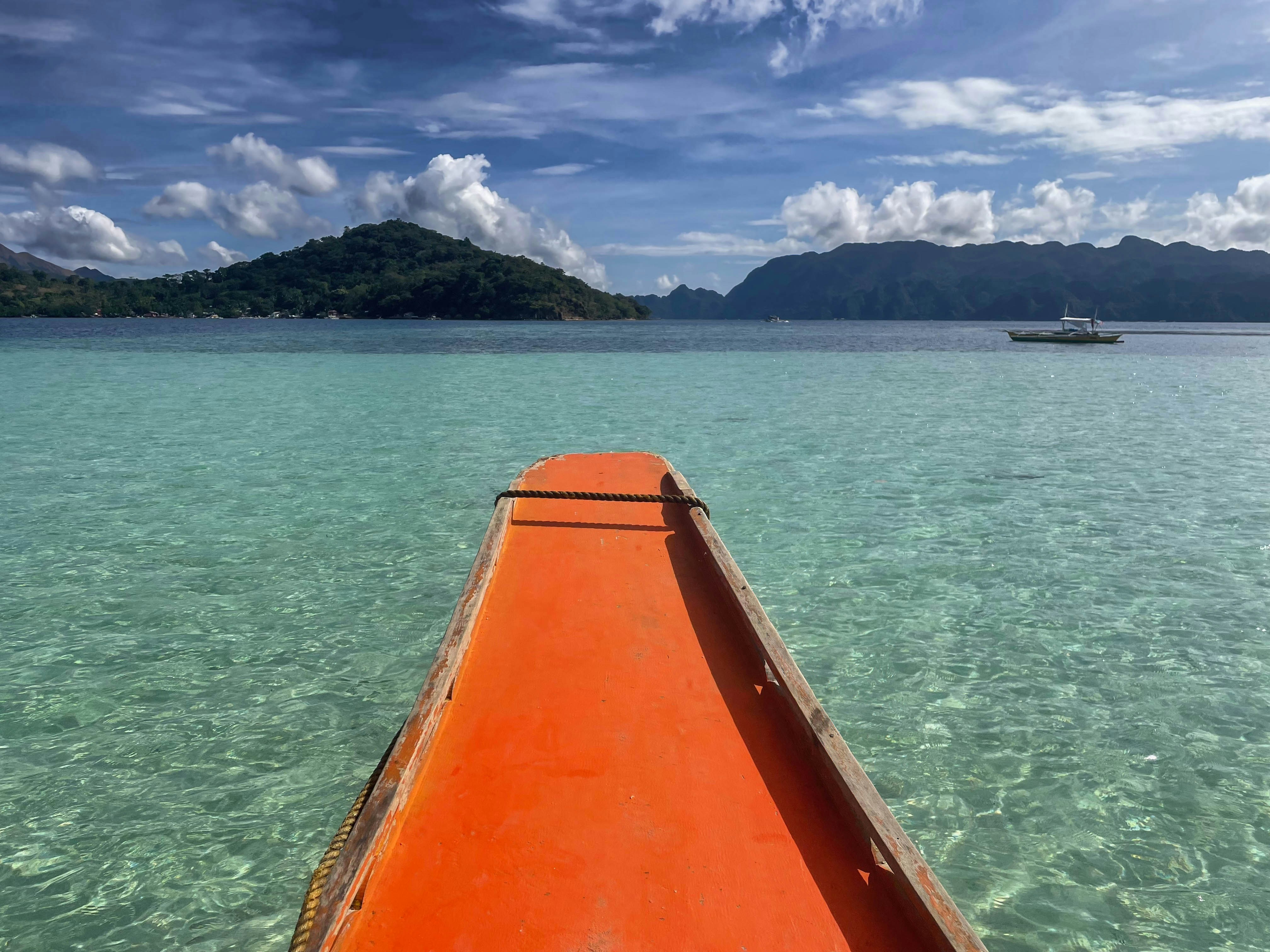 Orange Bow Cutting Through Turquoise Waters Toward a Cloud-Dusted Horizon
