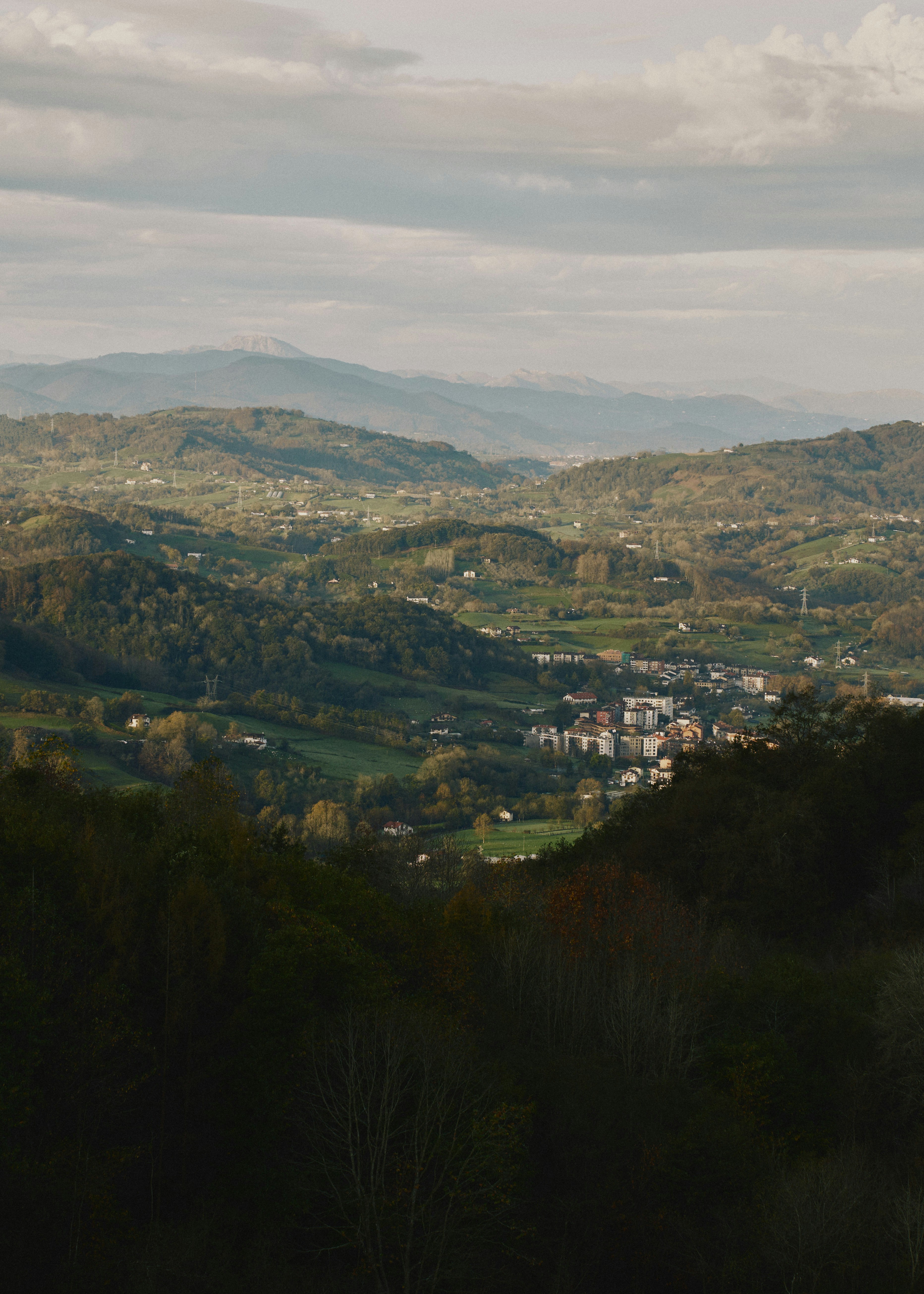 Valley Village Under Rolling Hills and Snow-Dusted Peaks