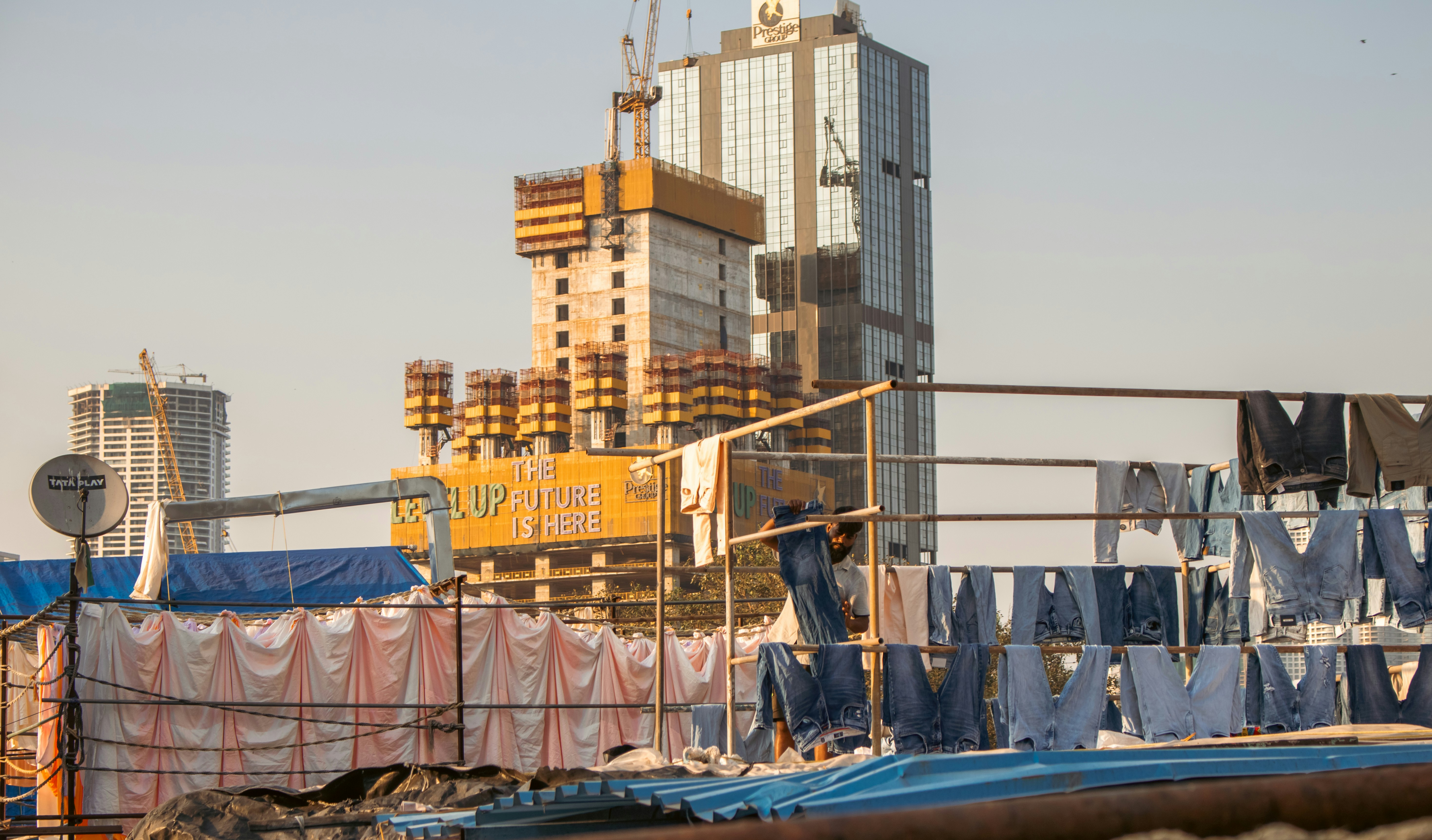 The Mumbai Lower Parel Skyline as seen from Dhobi Ghat, Mumbai's iconic open-air laundromat, located near Mahalaxmi station, that is one of the world's largest of its kind. The washers, known as dhobis, work in the open to wash clothes and linens from Mumbai's hotels and hospitals. Over one lakh (100,000) clothes are washed each day. Some of the wealthier dhobis have given up on manual cleaning and have now installed large mechanical washing and drying machines. The dhobis collect clothes from all parts of the city, from Colaba to Virar.