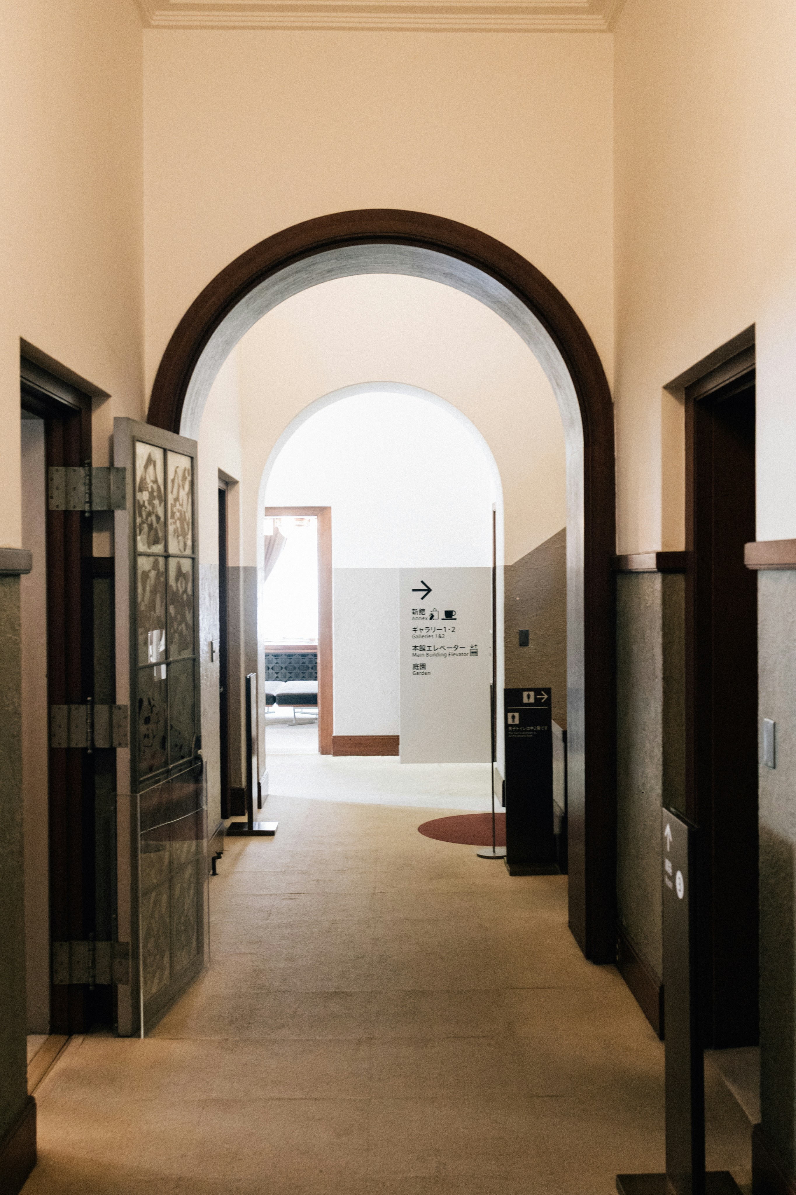 An arched hallway with doors and directional signs photo – Free ...