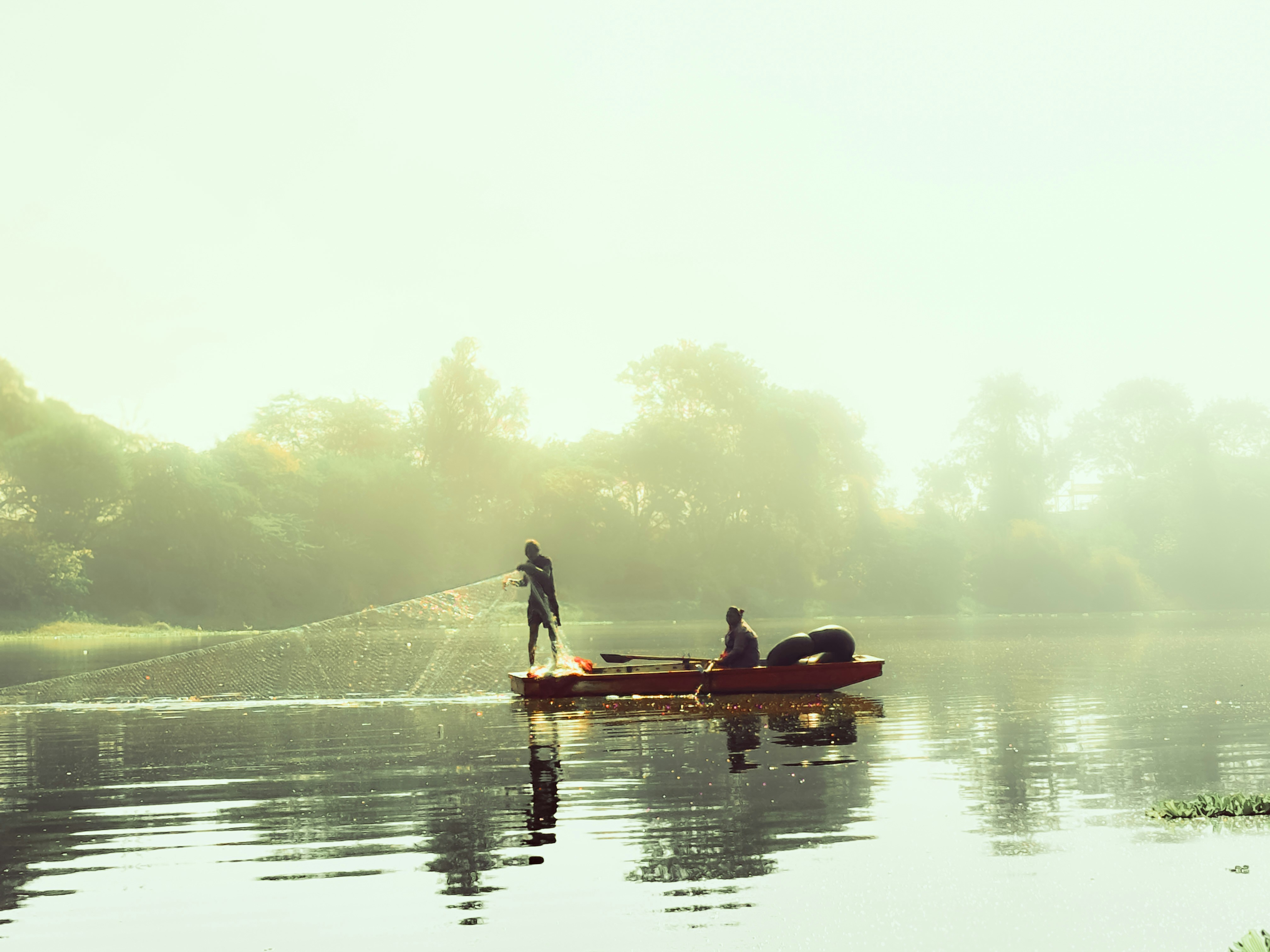 Dawn Net on a Glassy Lake: A Small Boat Casts Across Quiet Water