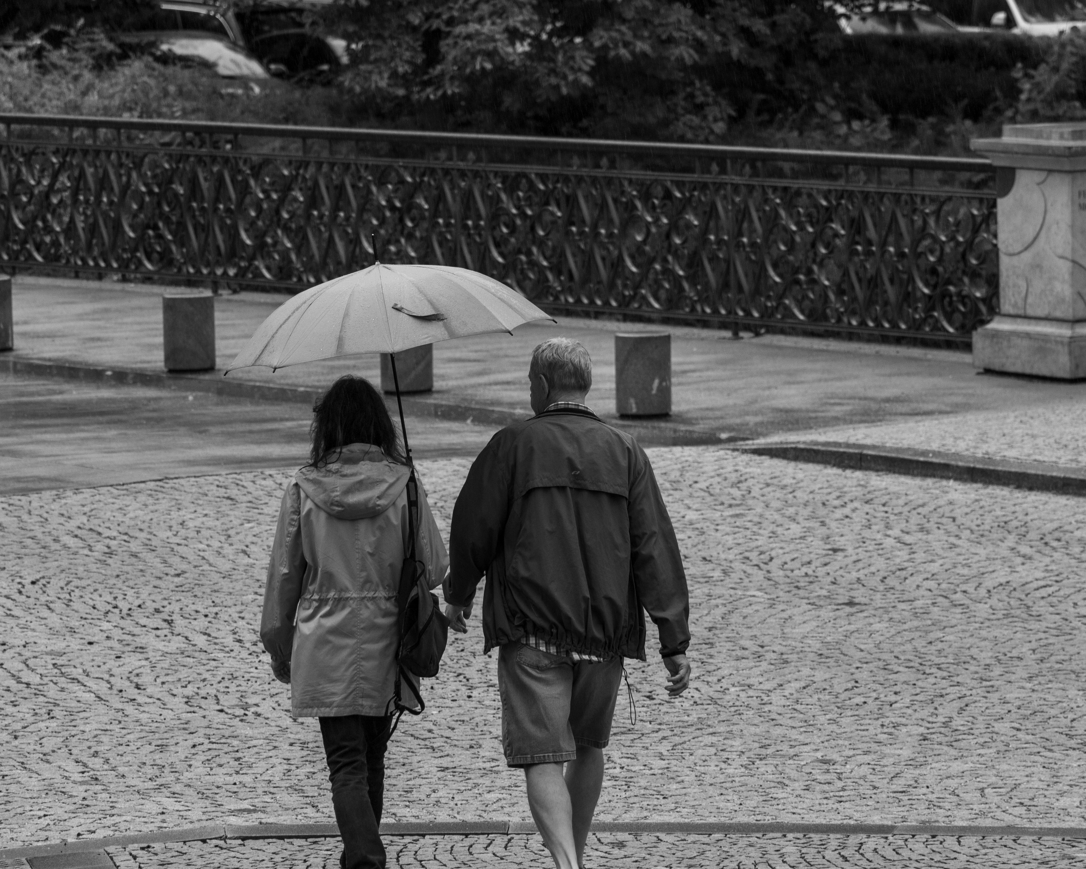 Two Shaded Walkers Beneath a Lone Umbrella
